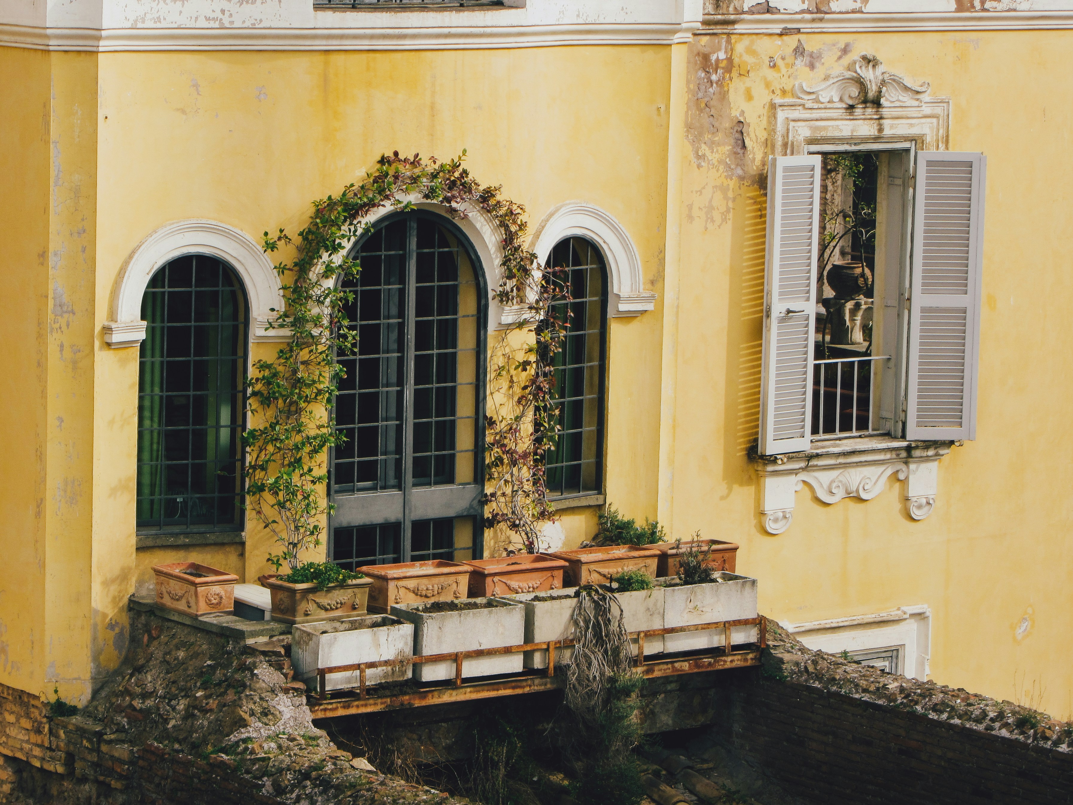 Sunlit Arcadia: Ivy-Framed Balcony Over a Worn Yellow Façade