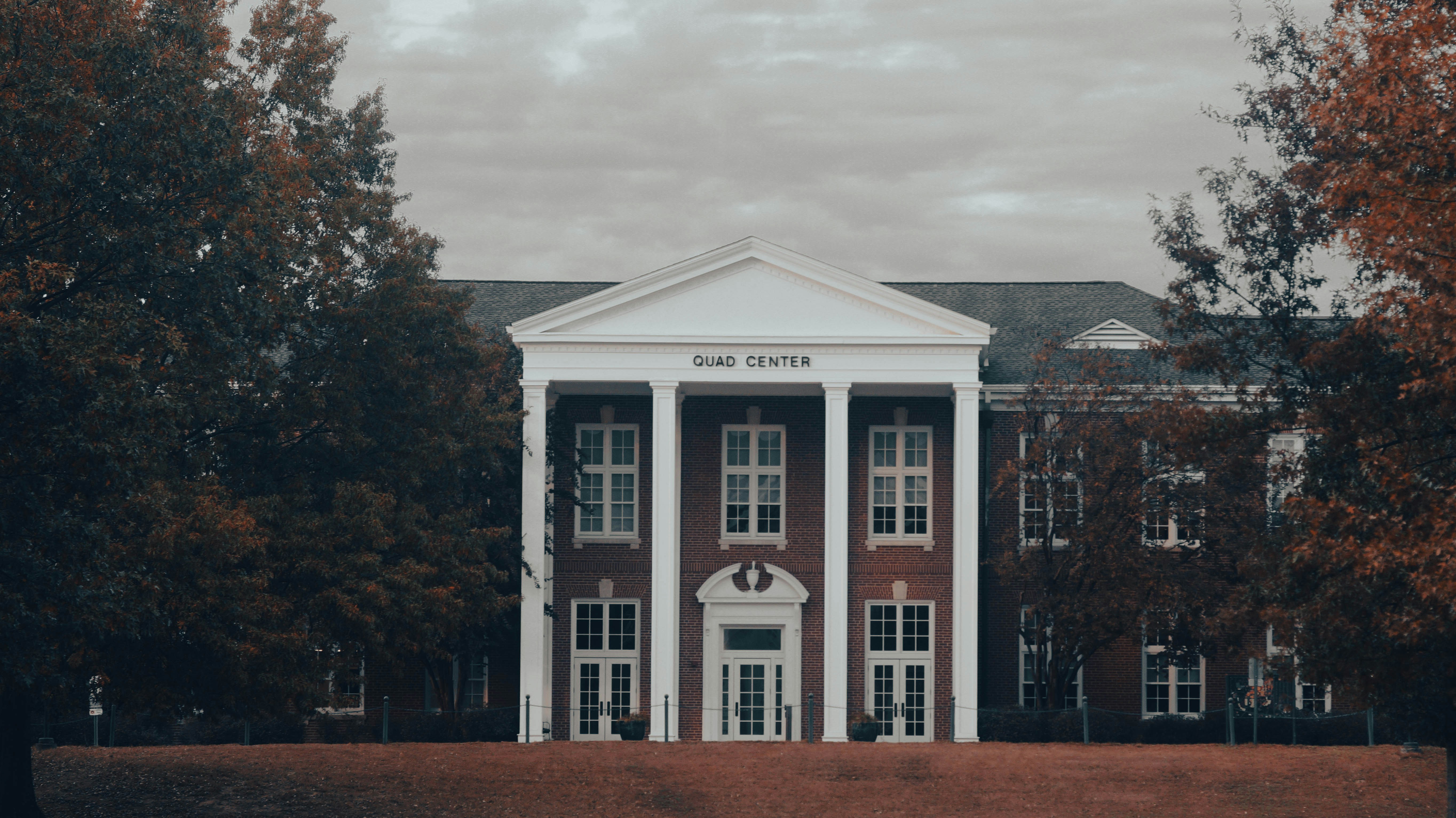 A large brick building with columns and a white roof photo – Free ...
