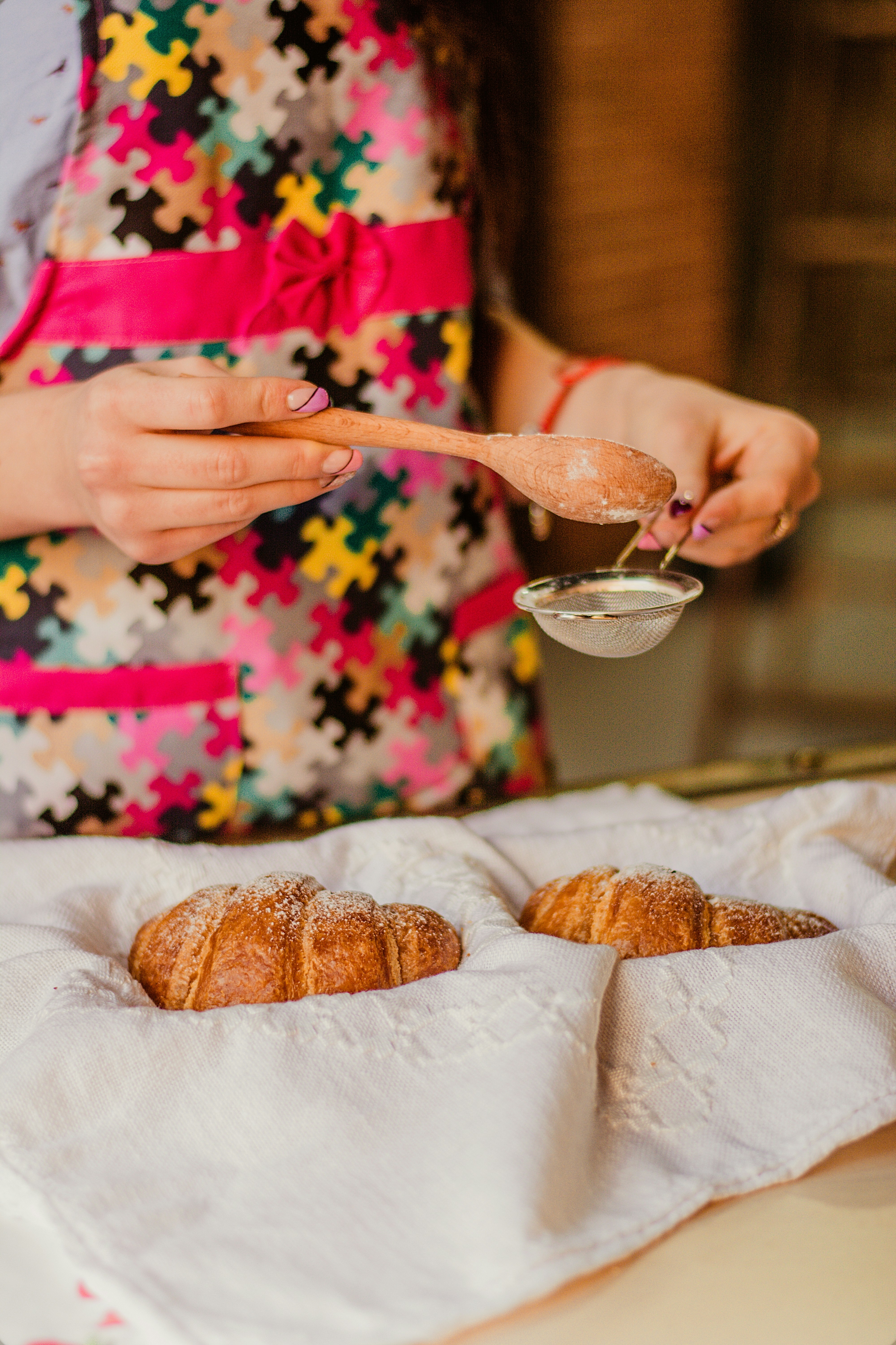 A woman holding a spoon in front of some croissants photo – Free ...