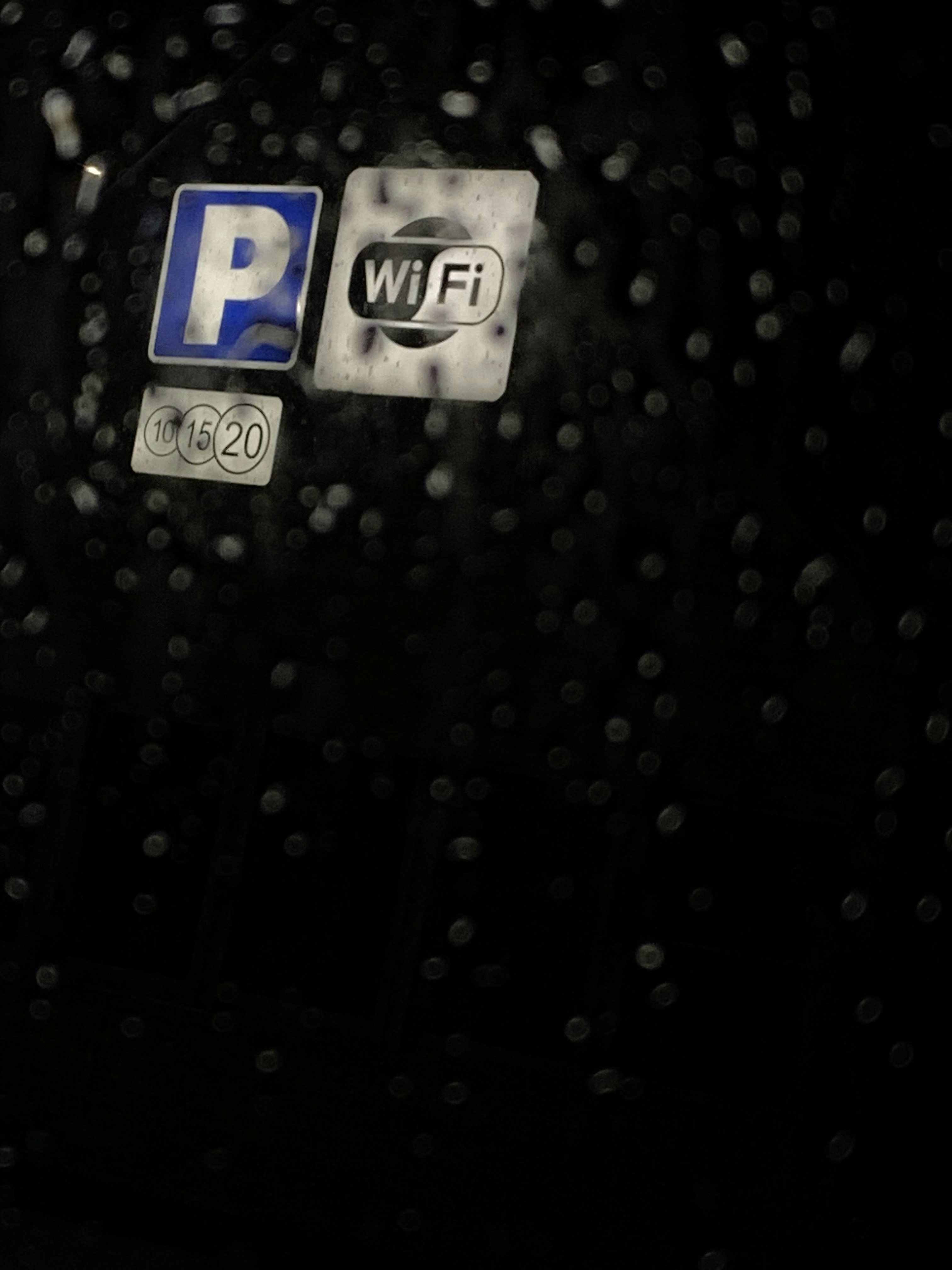 a close up of a parking sign with rain drops
