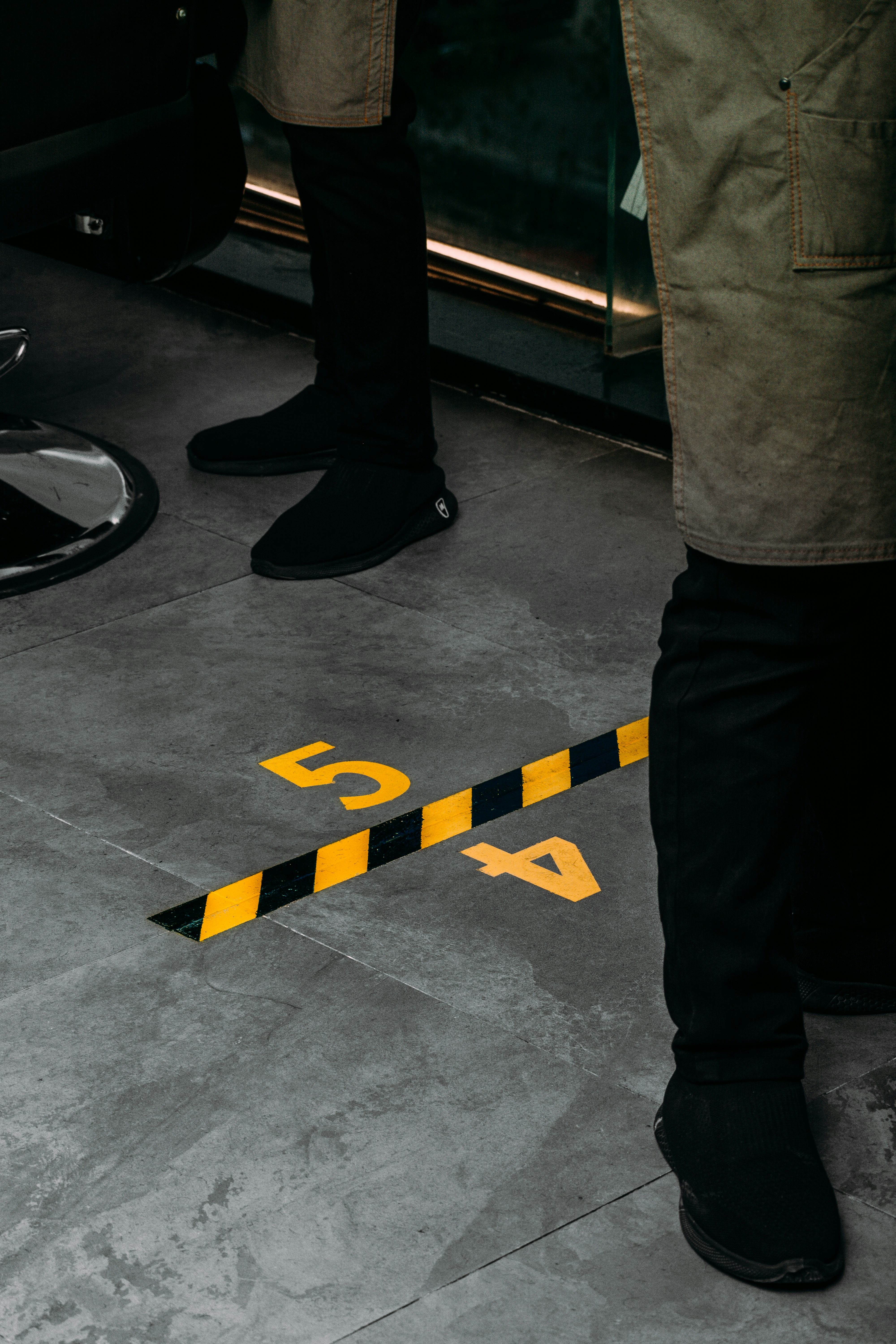 A pair of legs standing next to a yellow and black caution line photo ...