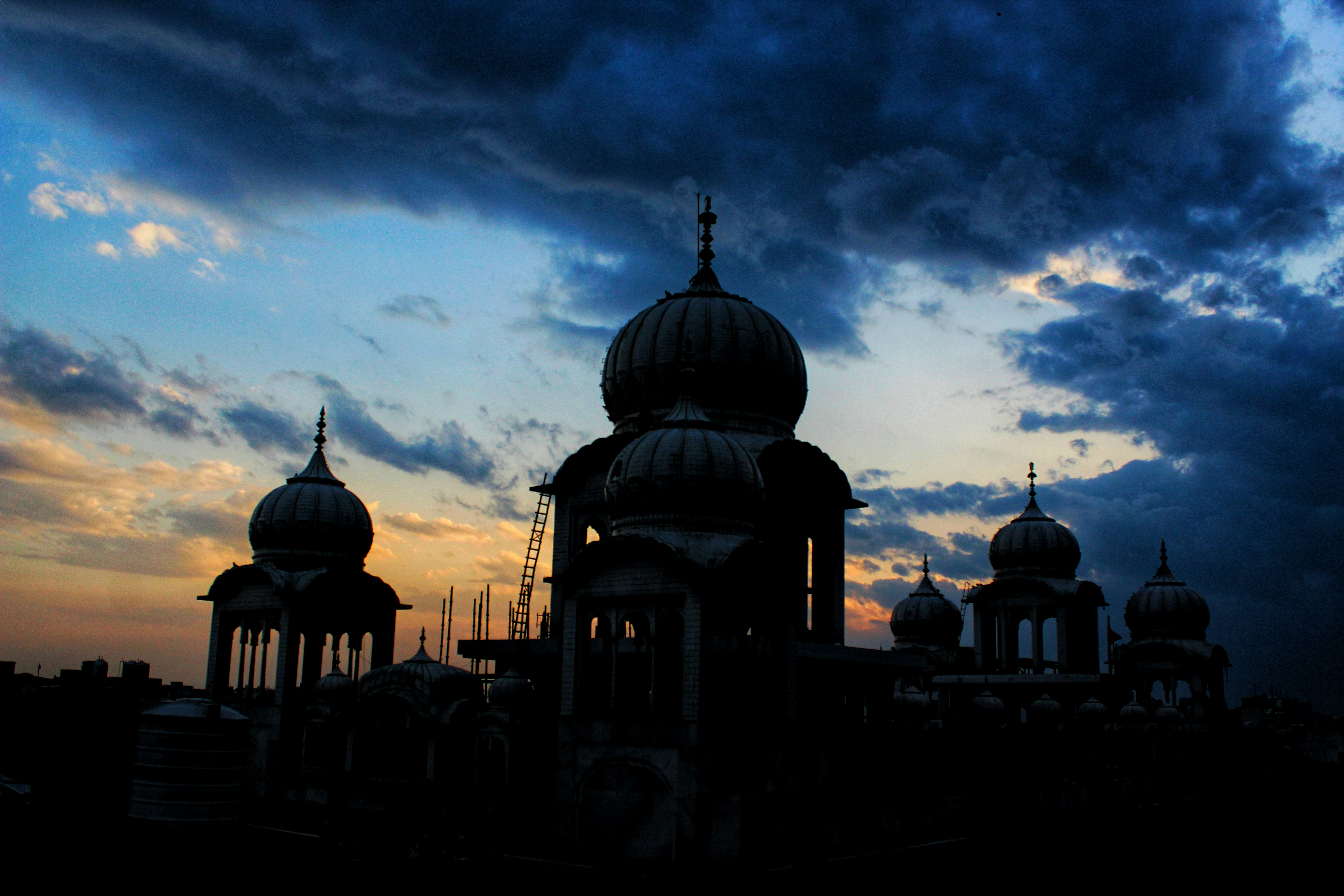 Silhouetted domes of a historic building against a dramatic twilight sky, showcasing a blend of architecture and nature's palette.