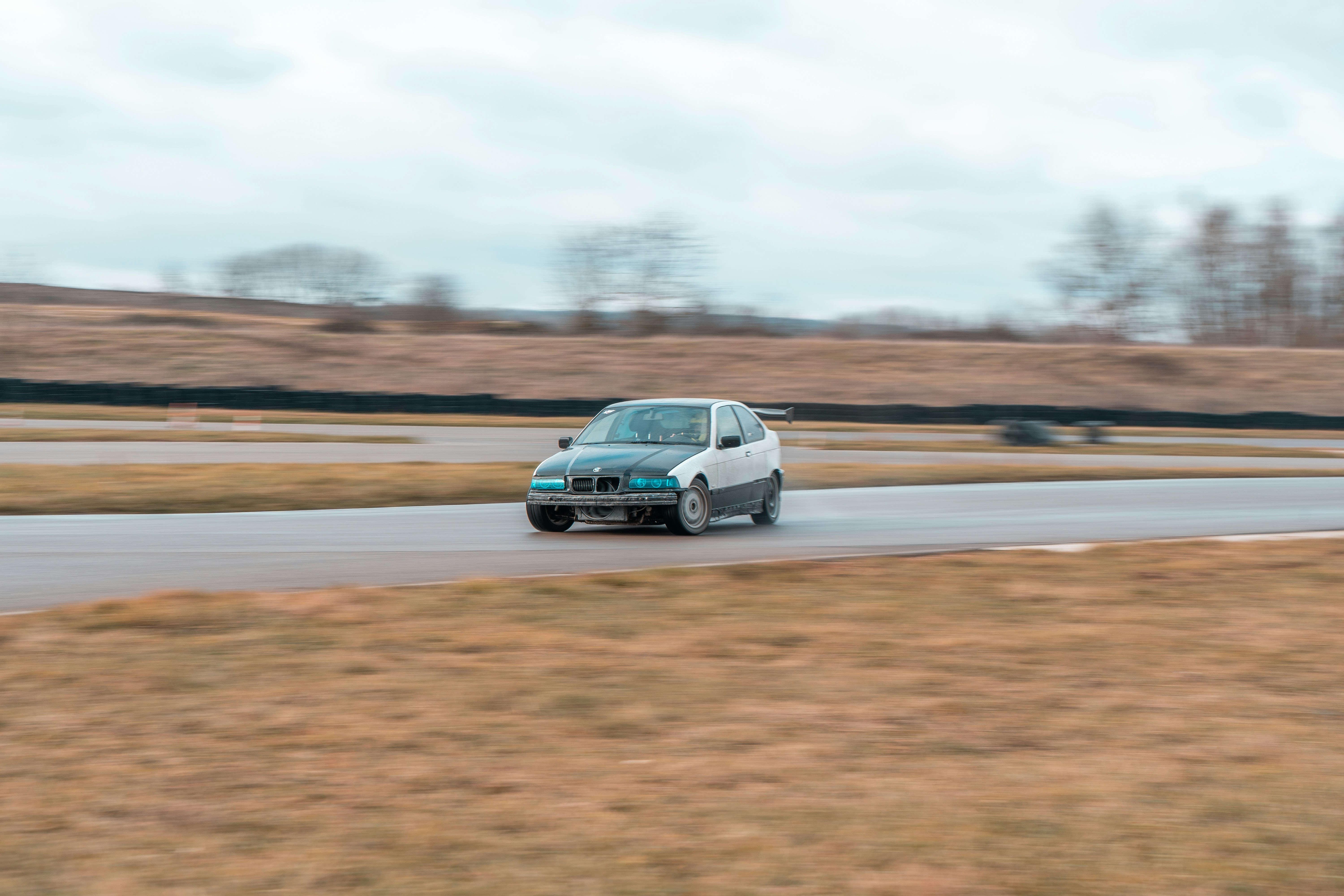 A small car driving down a road near a field photo – Free Wallpapers ...