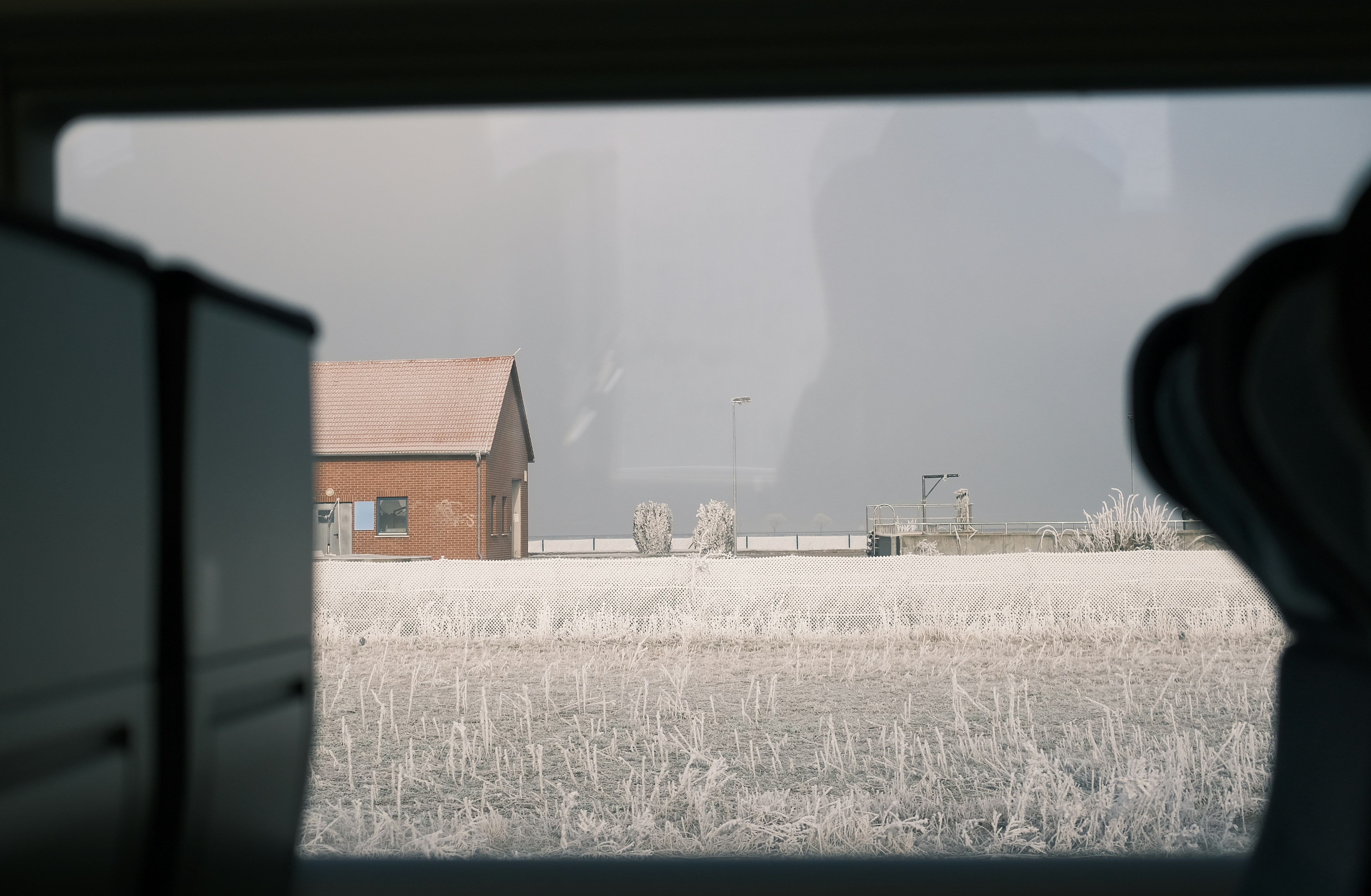 Snow-covered field framed by a van and window in a moving view