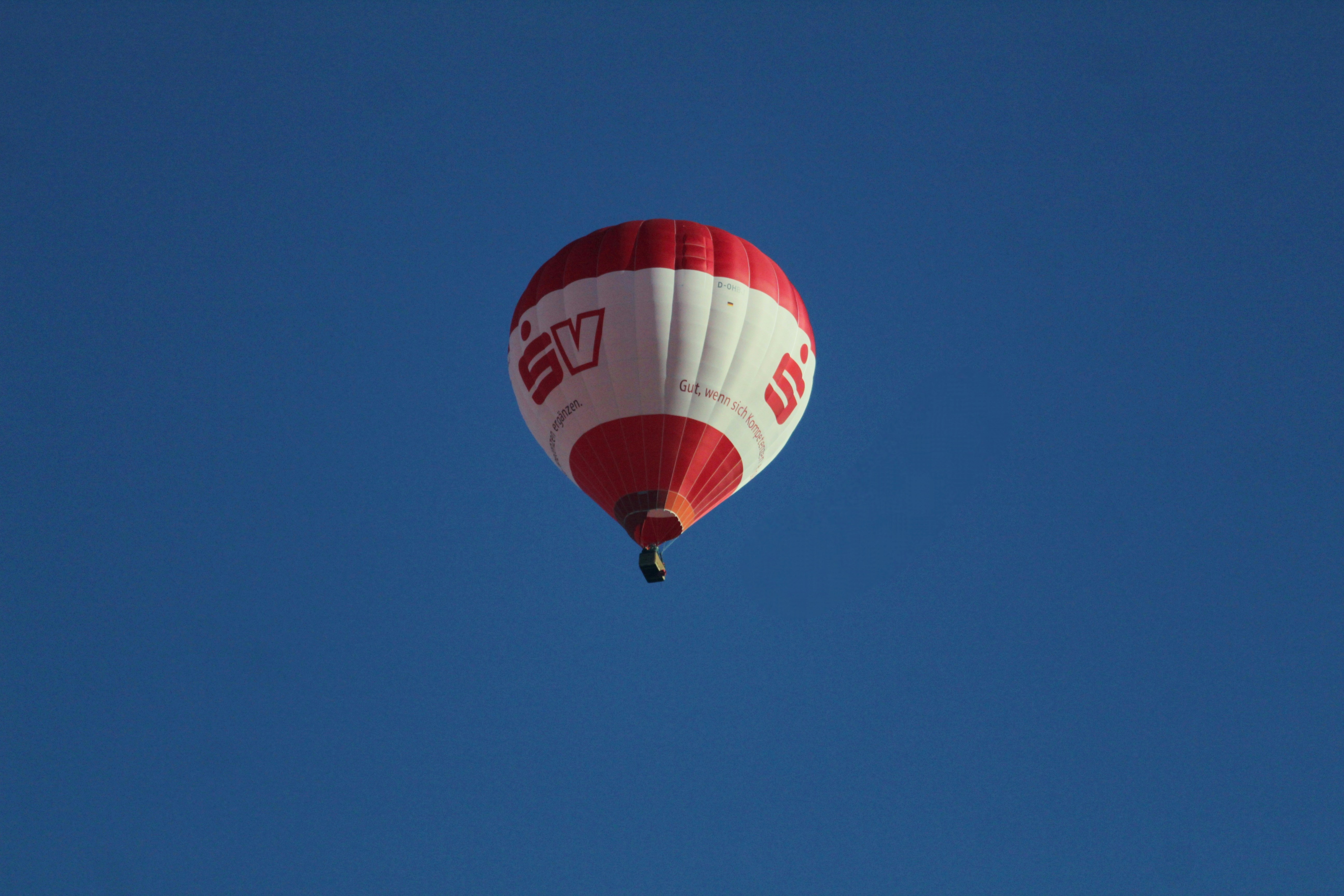 Red-and-White Balloon Soaring Against Clear Sky