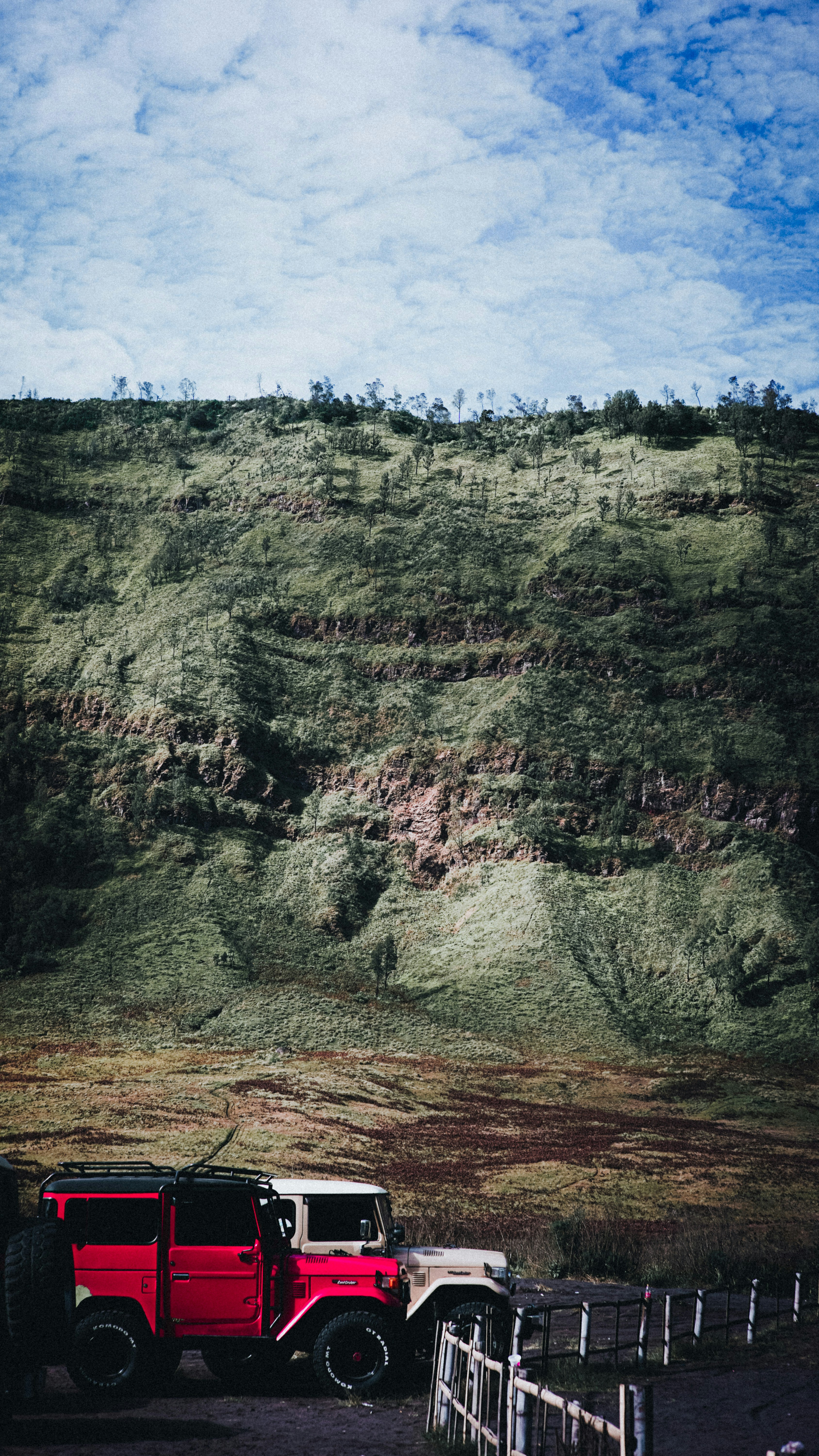 Crimson Jeep at the Foot of a Verdant Ridge