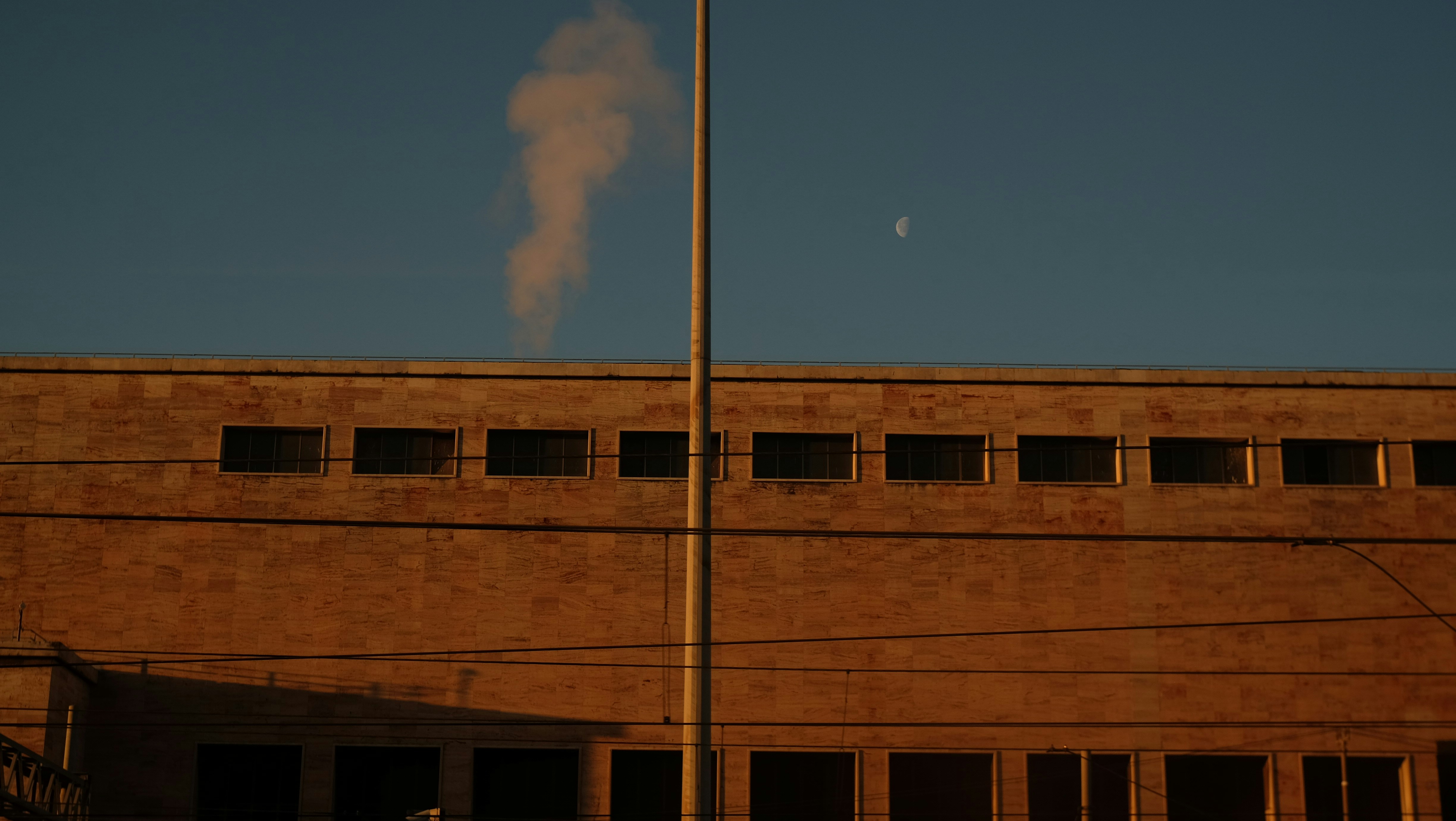 Dusk at the Brick Factory: Smoke Plume, Moon, and a Central Pole
