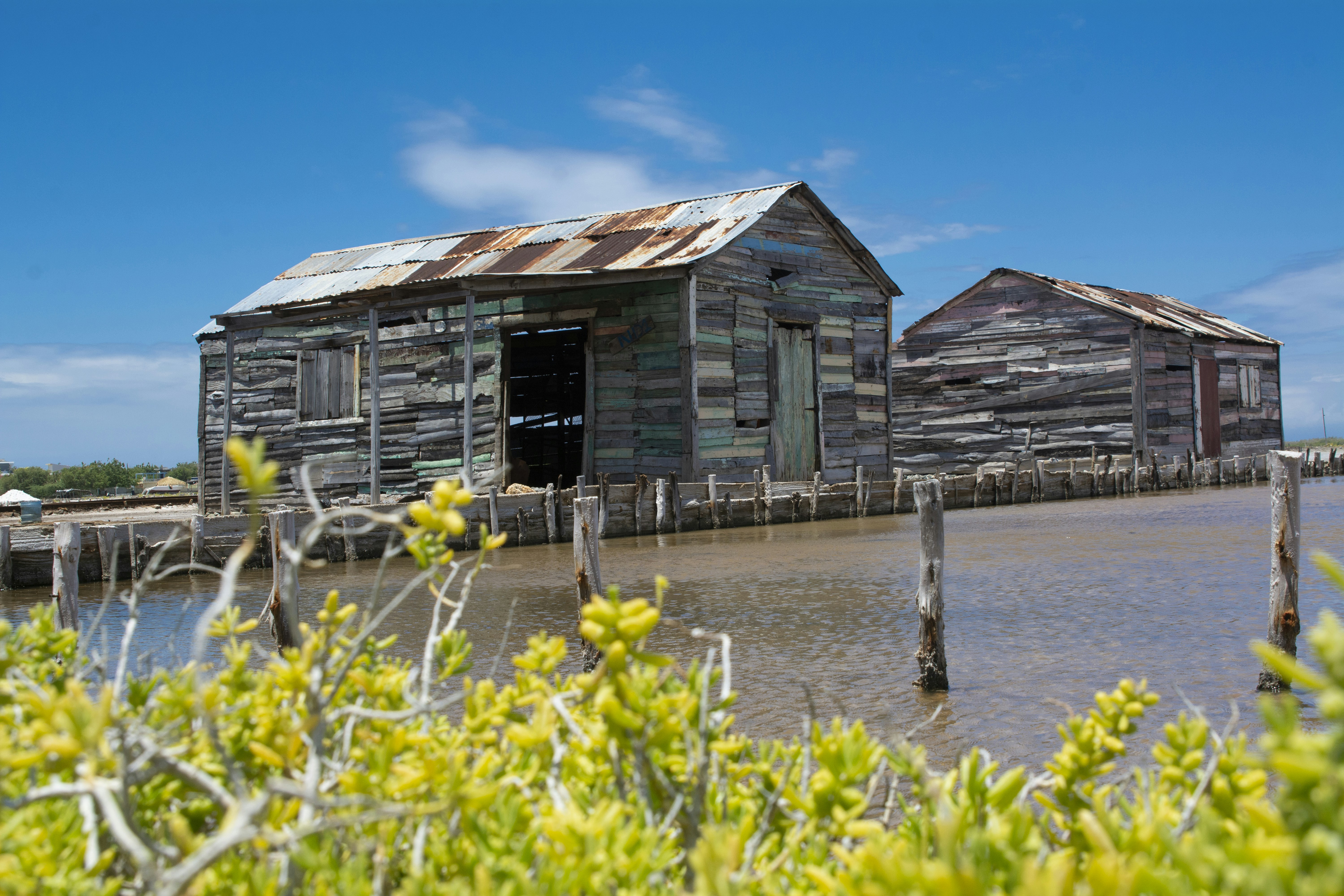 An old wooden shack sitting on top of a body of water photo – Free Baní ...