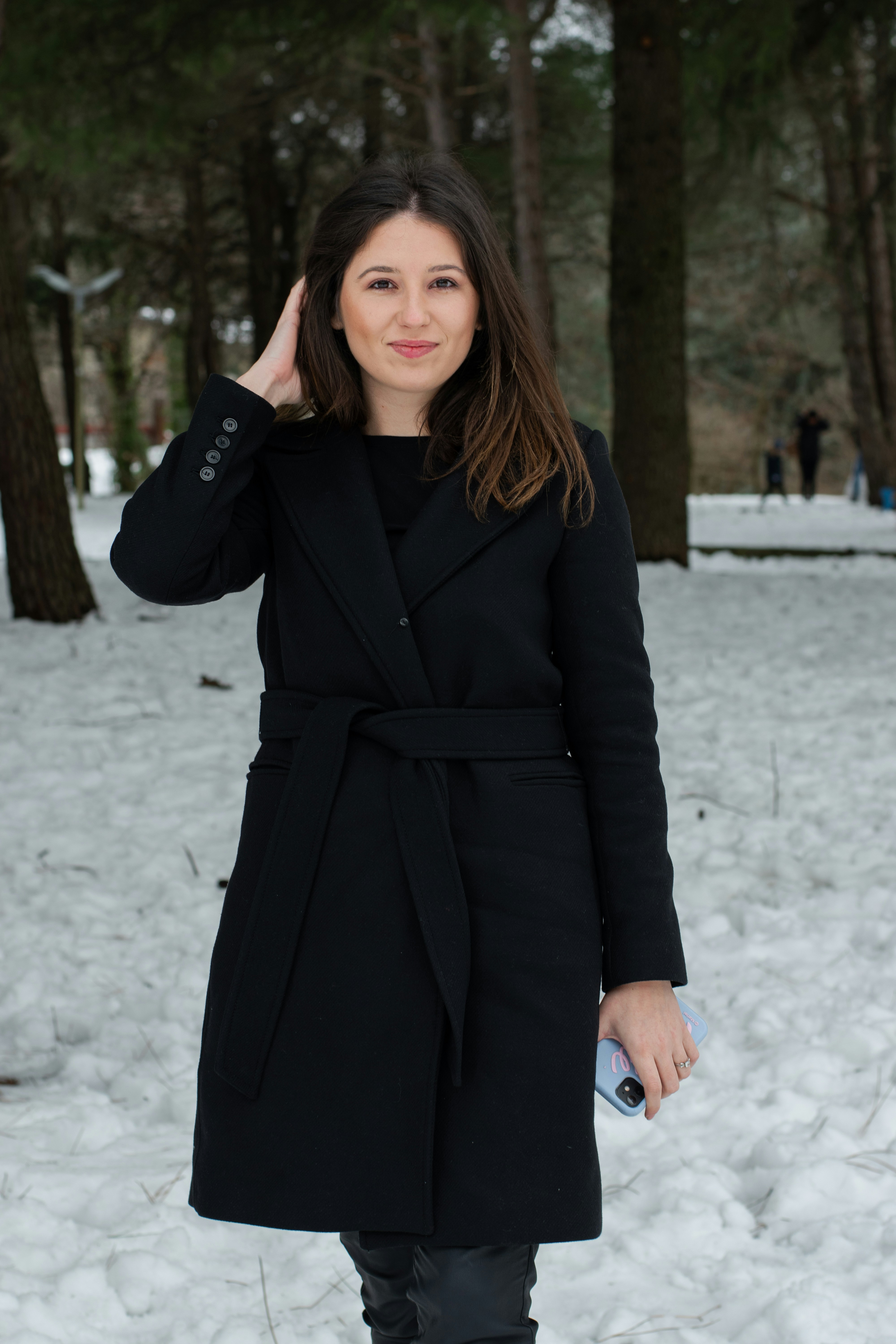 Winter Quiet: Portrait in a Belted Black Coat Amid Snowy Pines
