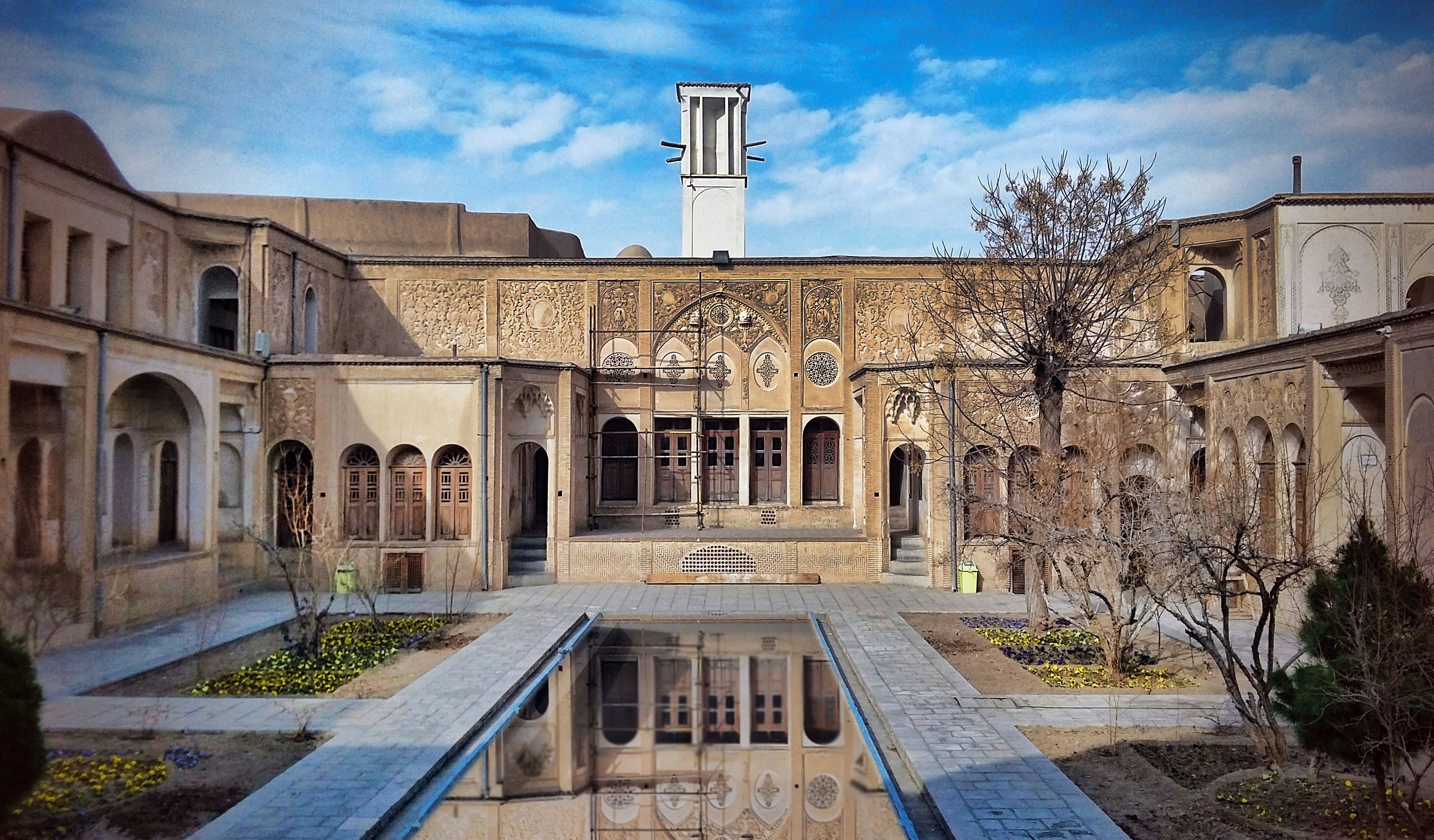 Historic courtyard of Borujerdi House with intricate facade and central reflecting pool under a clear sky.