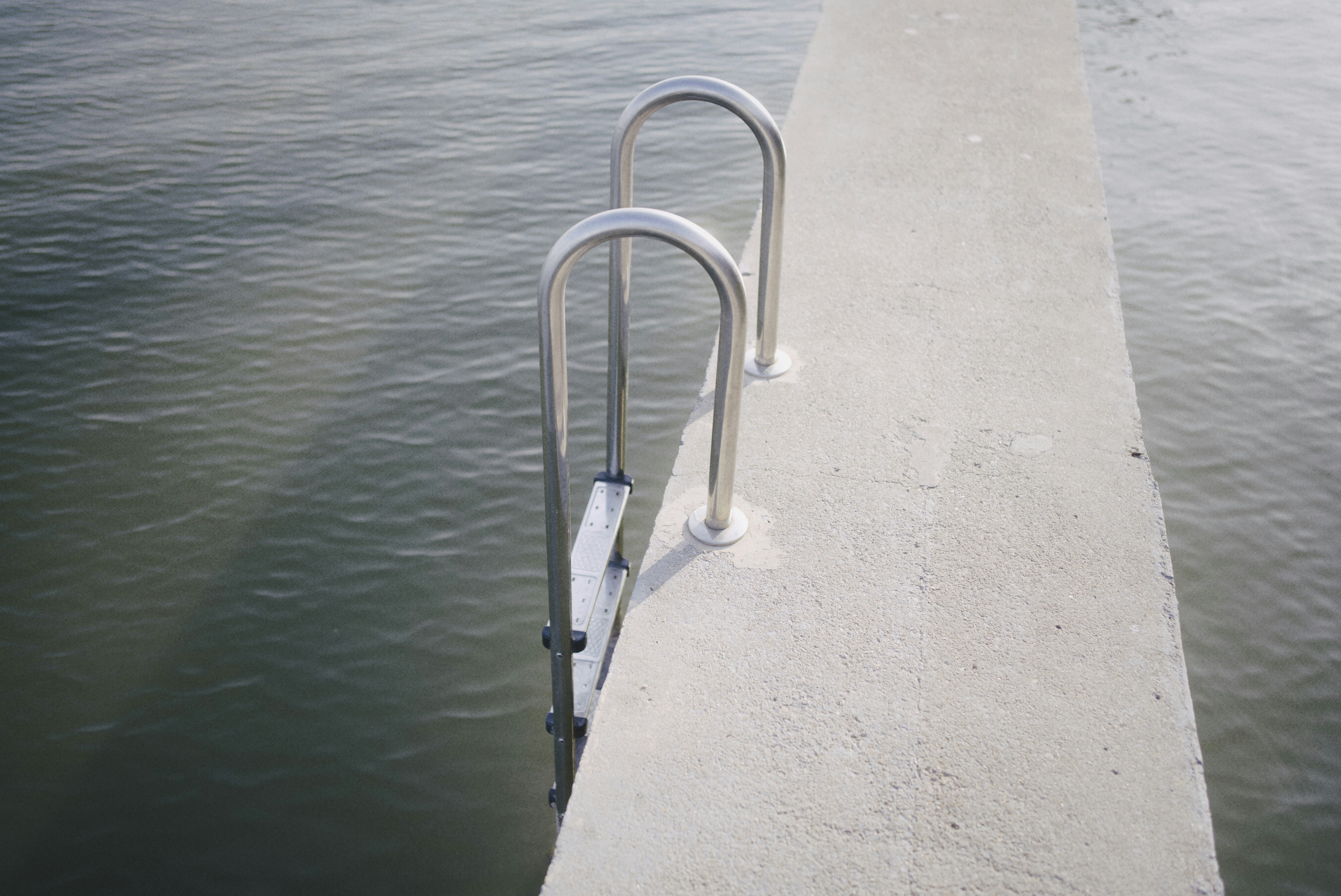 Laddered Edge: Concrete Pier Reaching Toward Glassy Water