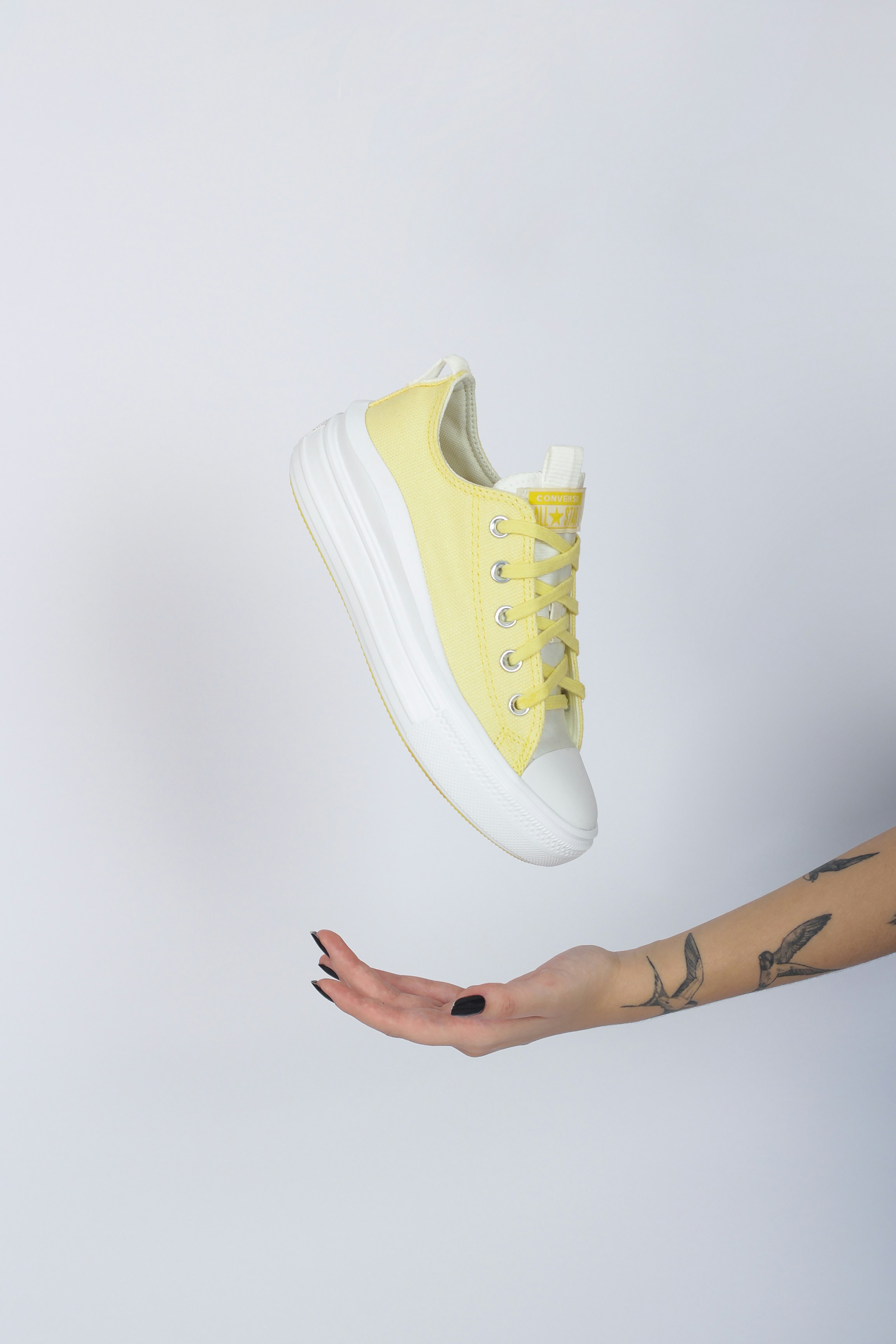 Yellow Sneaker Levitation: Studio Lift Over a Tattooed Hand