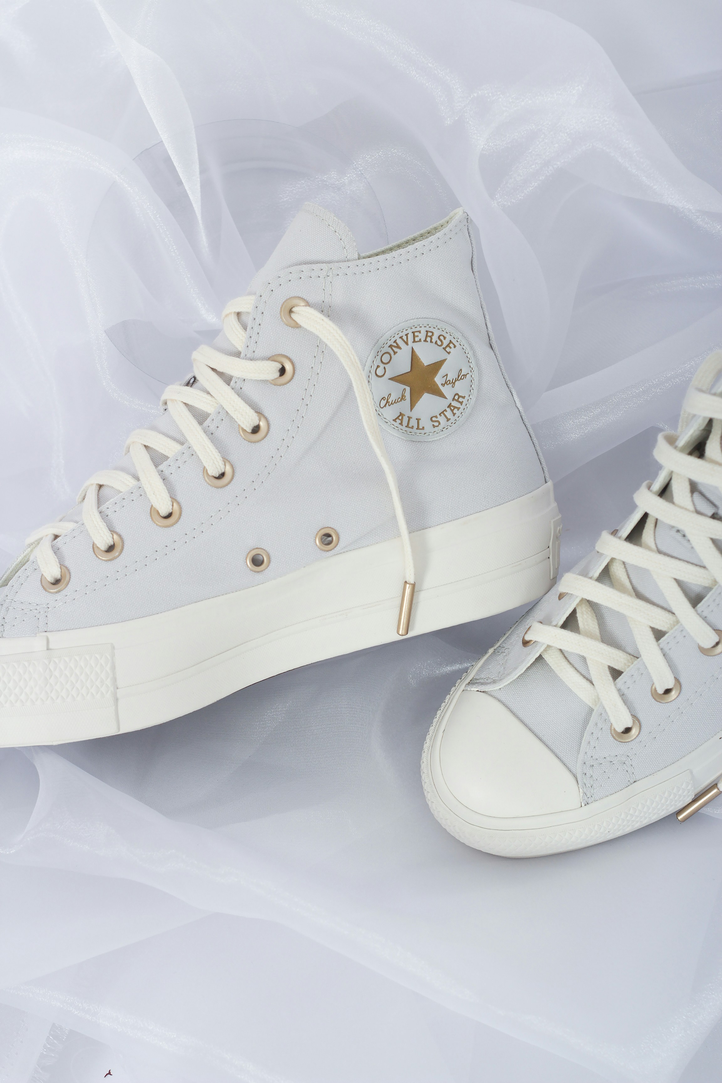 Converse Quiet: White High-Tops Rest on Sheer Fabric with Prominent Logo