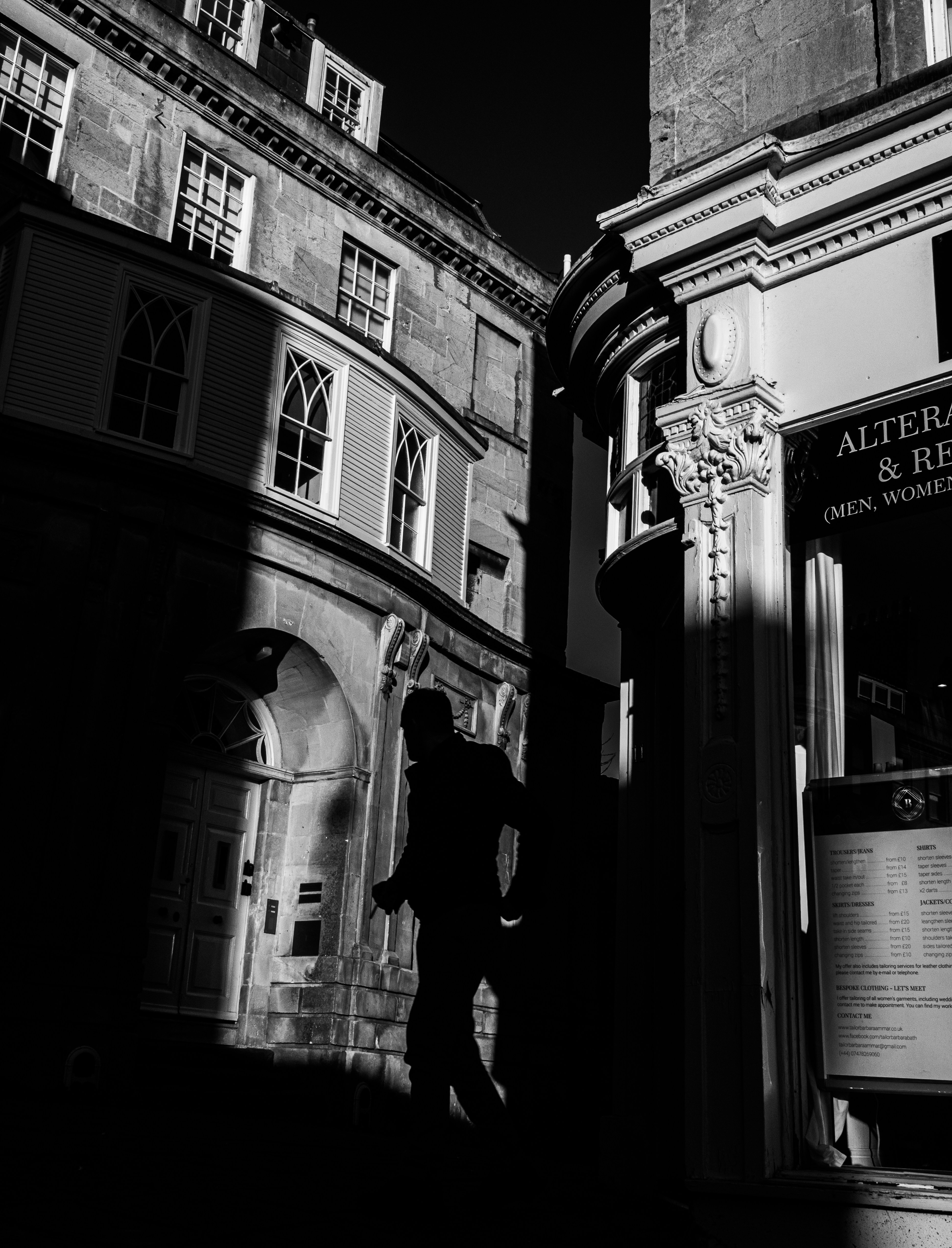 A black and white photo of a person walking past a building photo ...