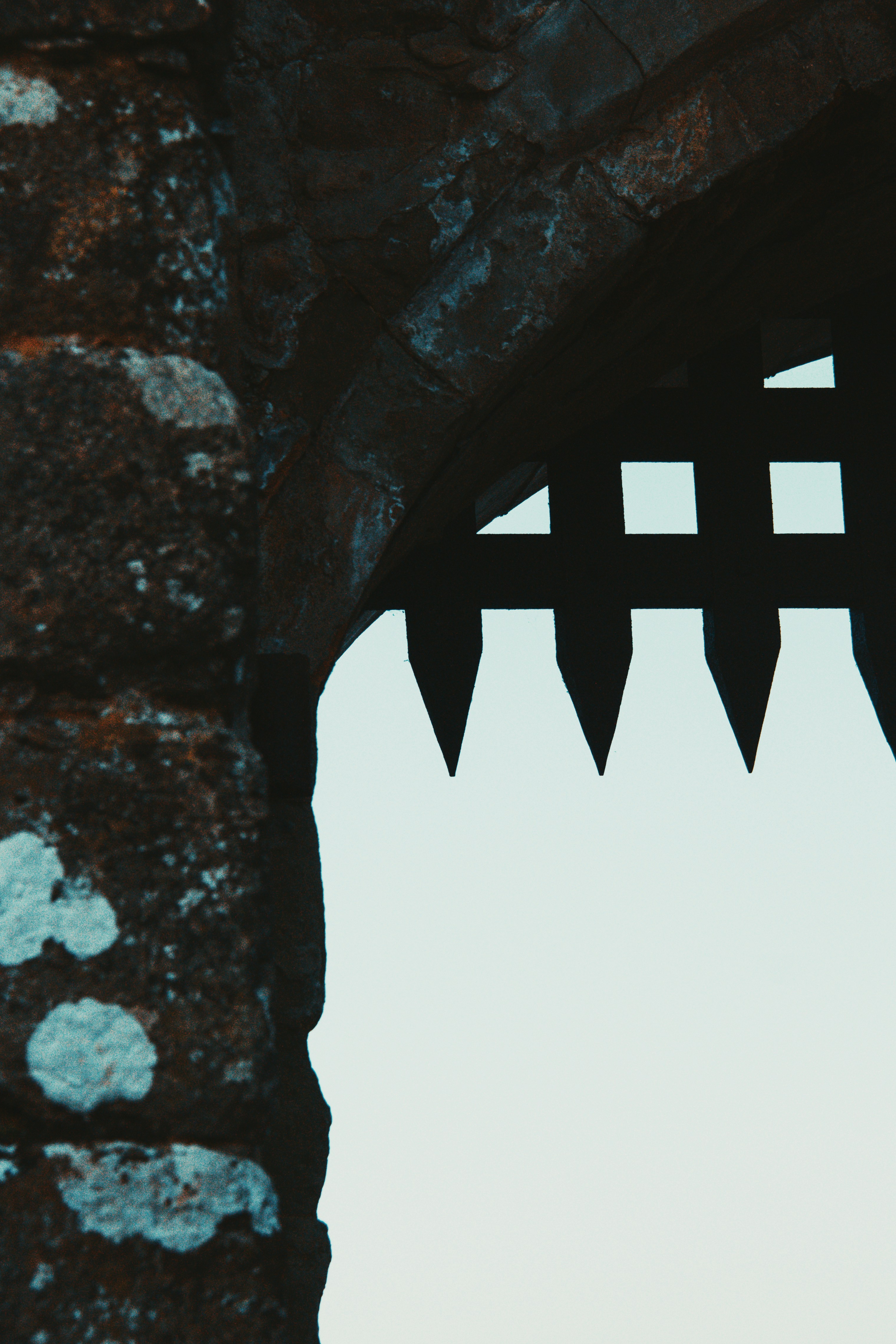 Stone Arch Gate: Teeth of a Weathered Ruin Against a Pale Sky