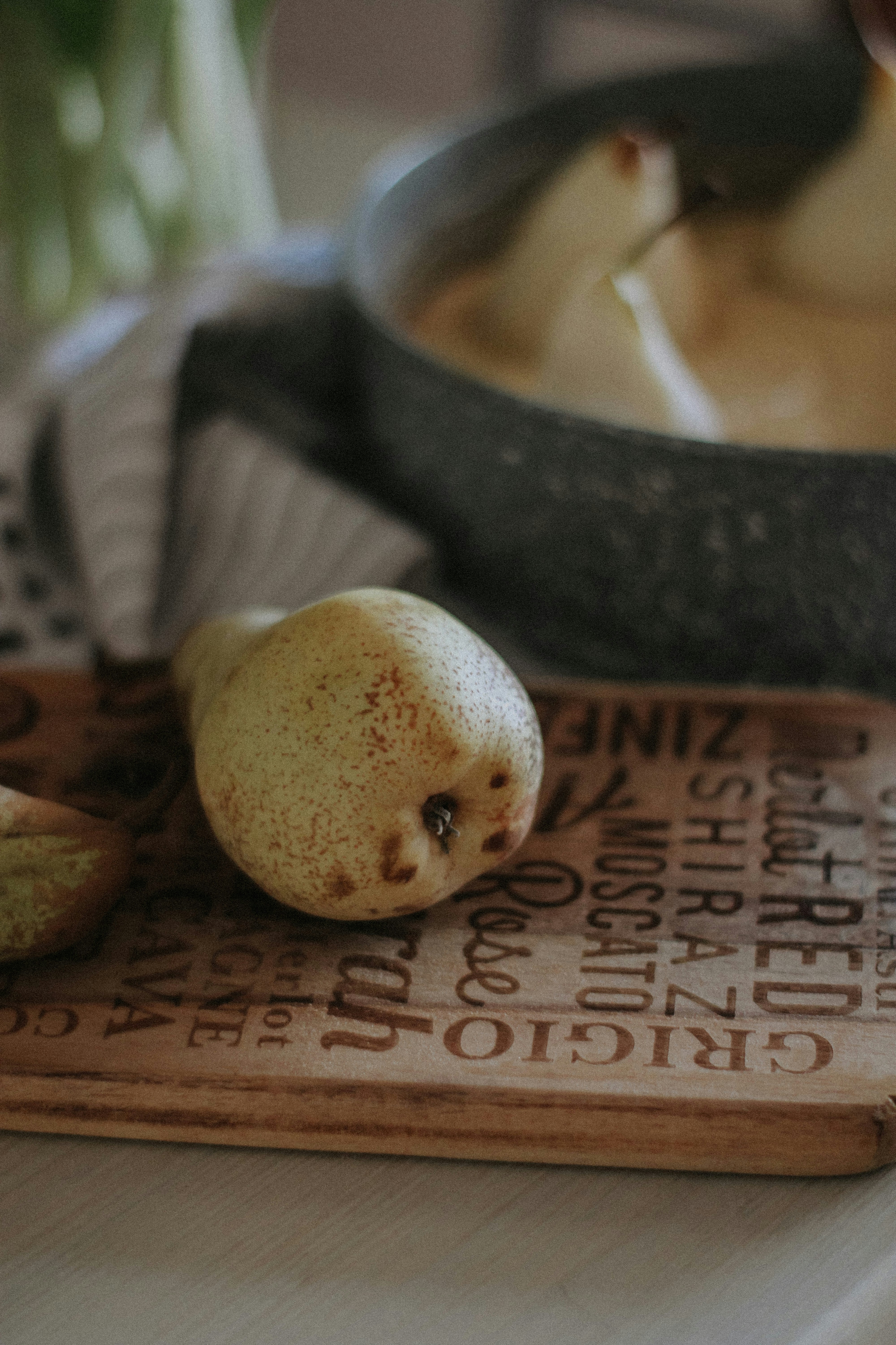 a pear sitting on a cutting board next to a bowl of dip