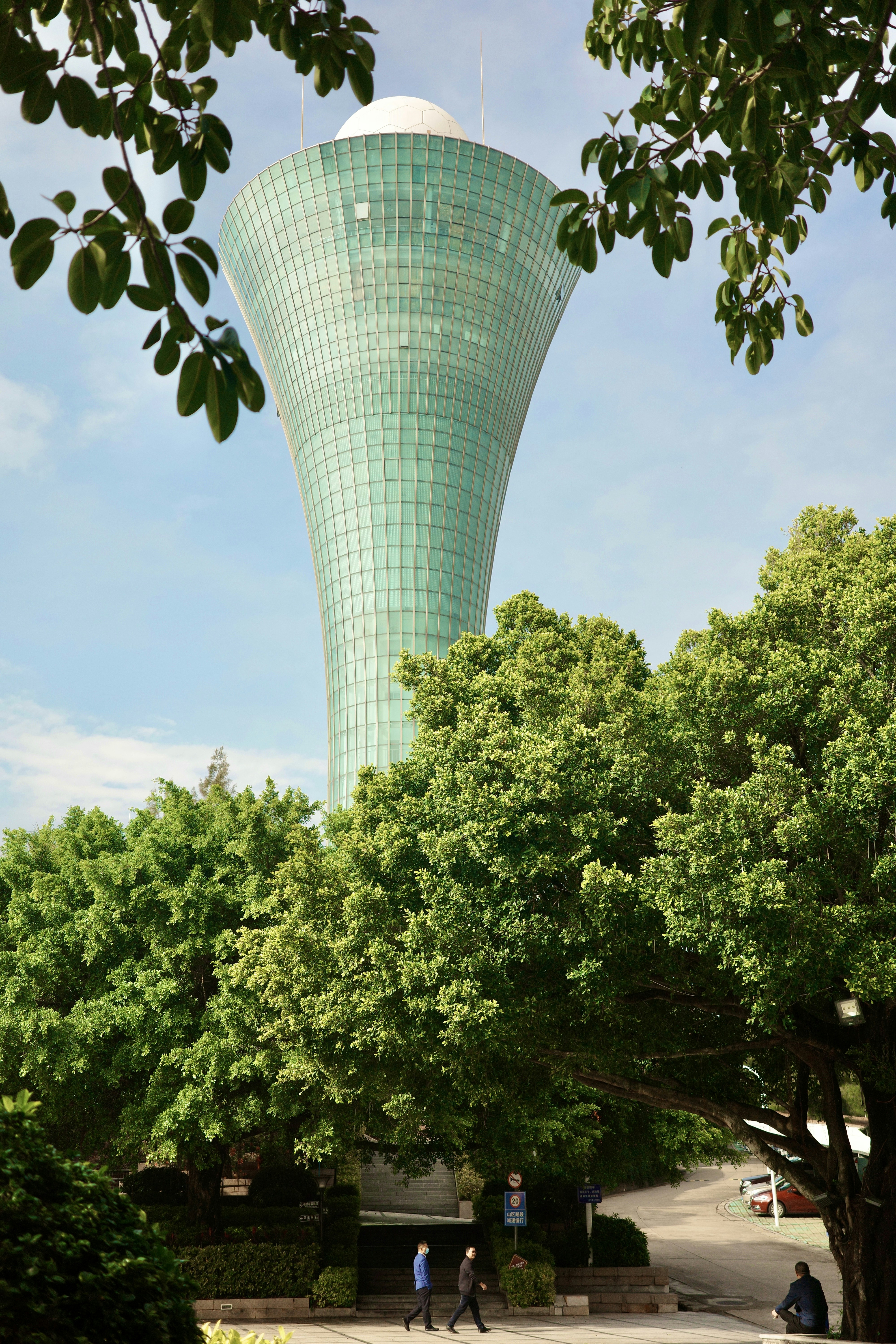 A tall green building with a sky scraper in the background photo – Free ...