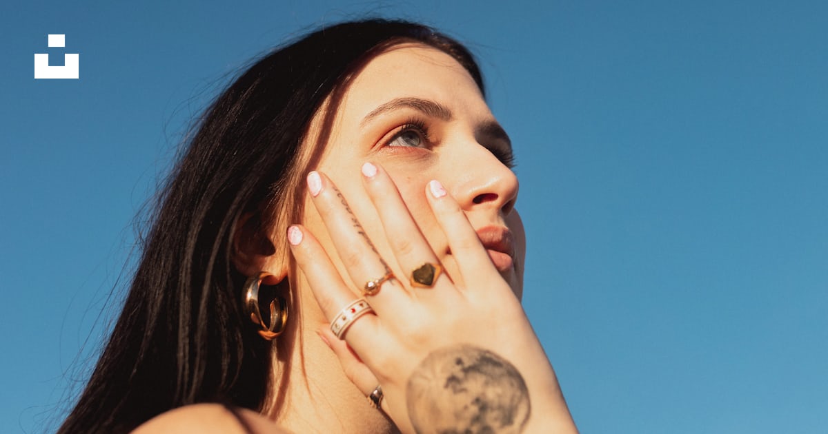A Woman With A Tattoo On Her Arm Holding Her Hand Up To Her Face Photo
