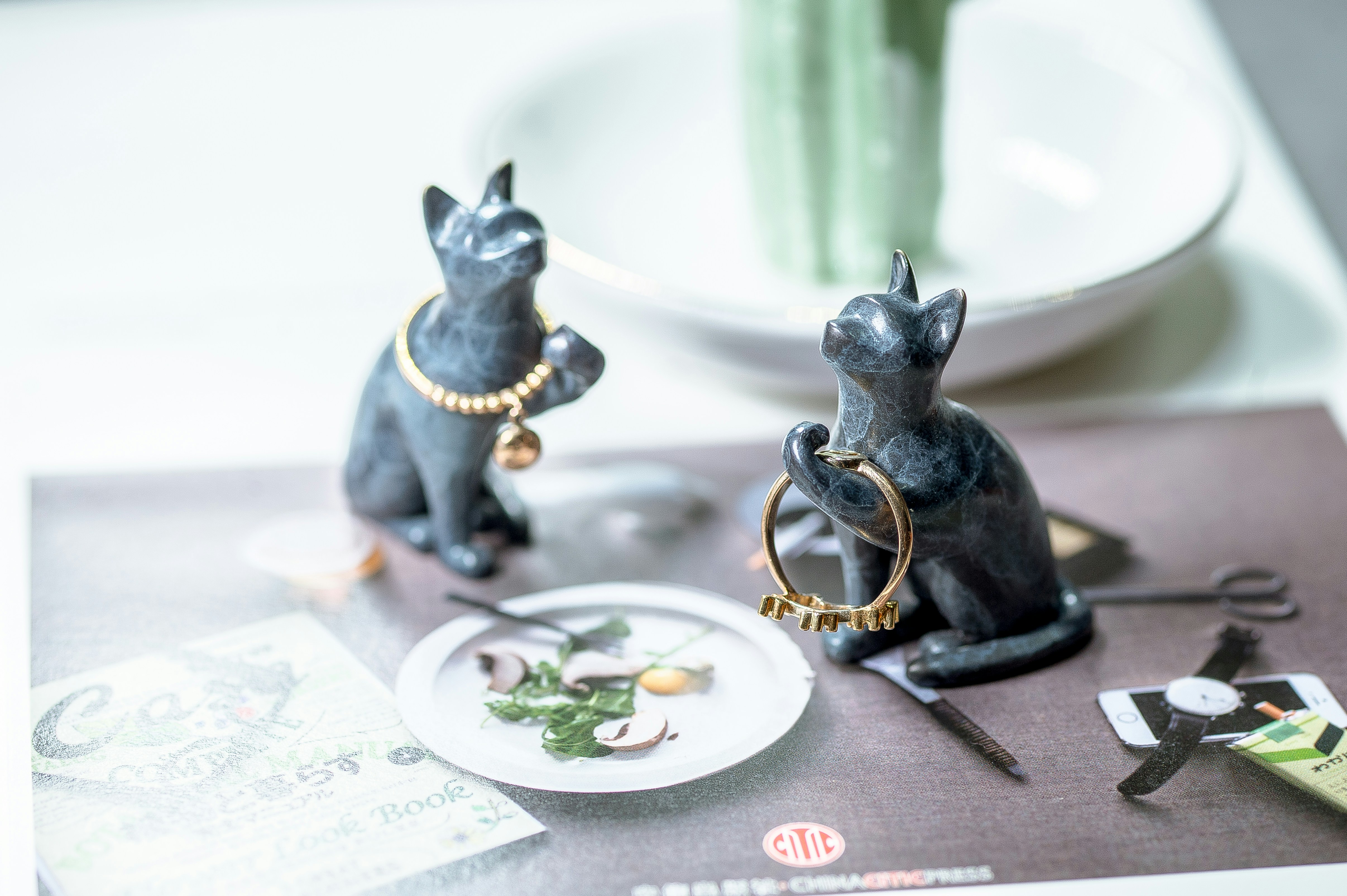 Kitty Jewelry: Two decorative cats with a ring and beads on a tabletop