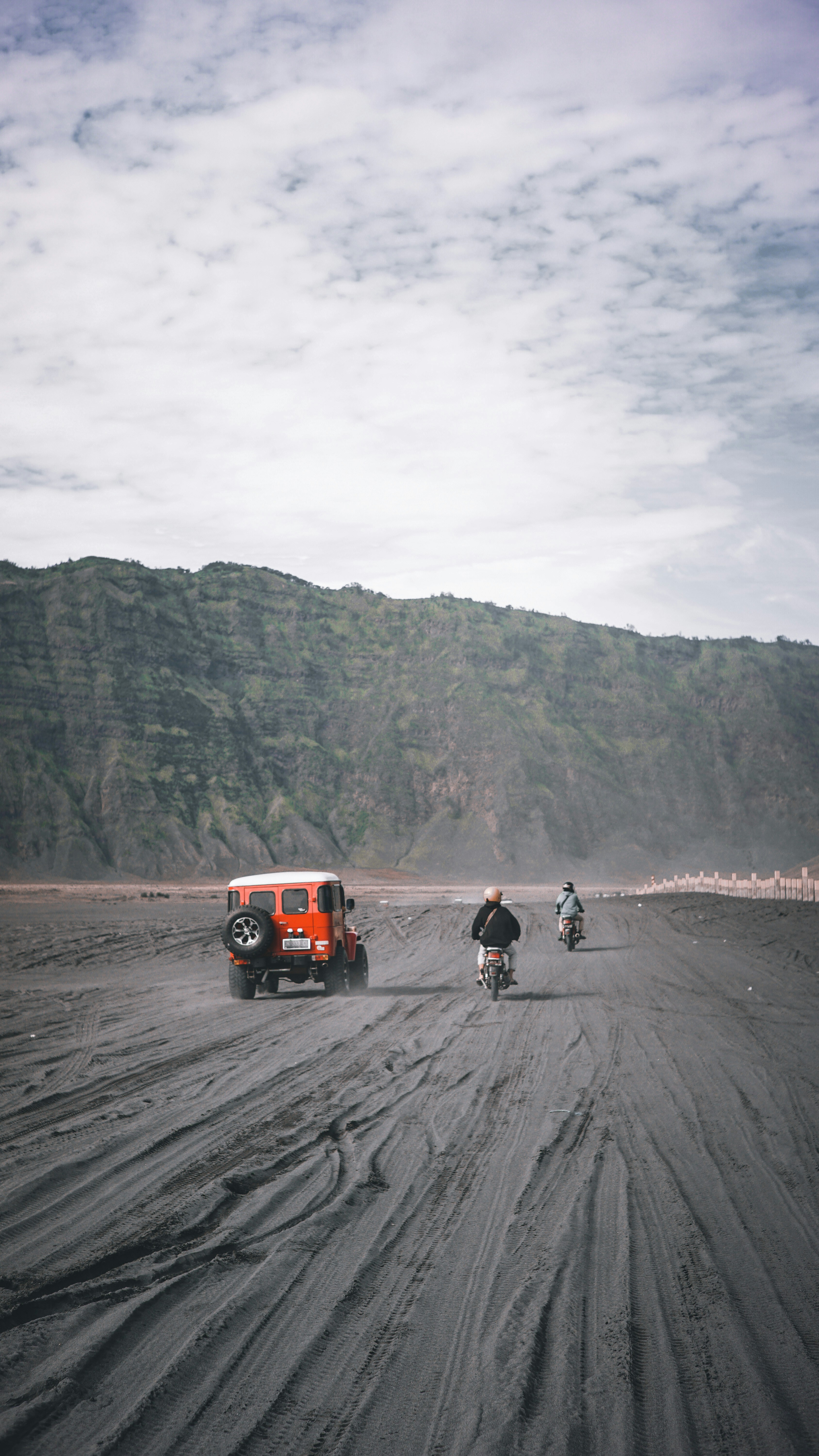 Crimson Jeep Rides the Dark Sand Along a Cliff-Backed Dune