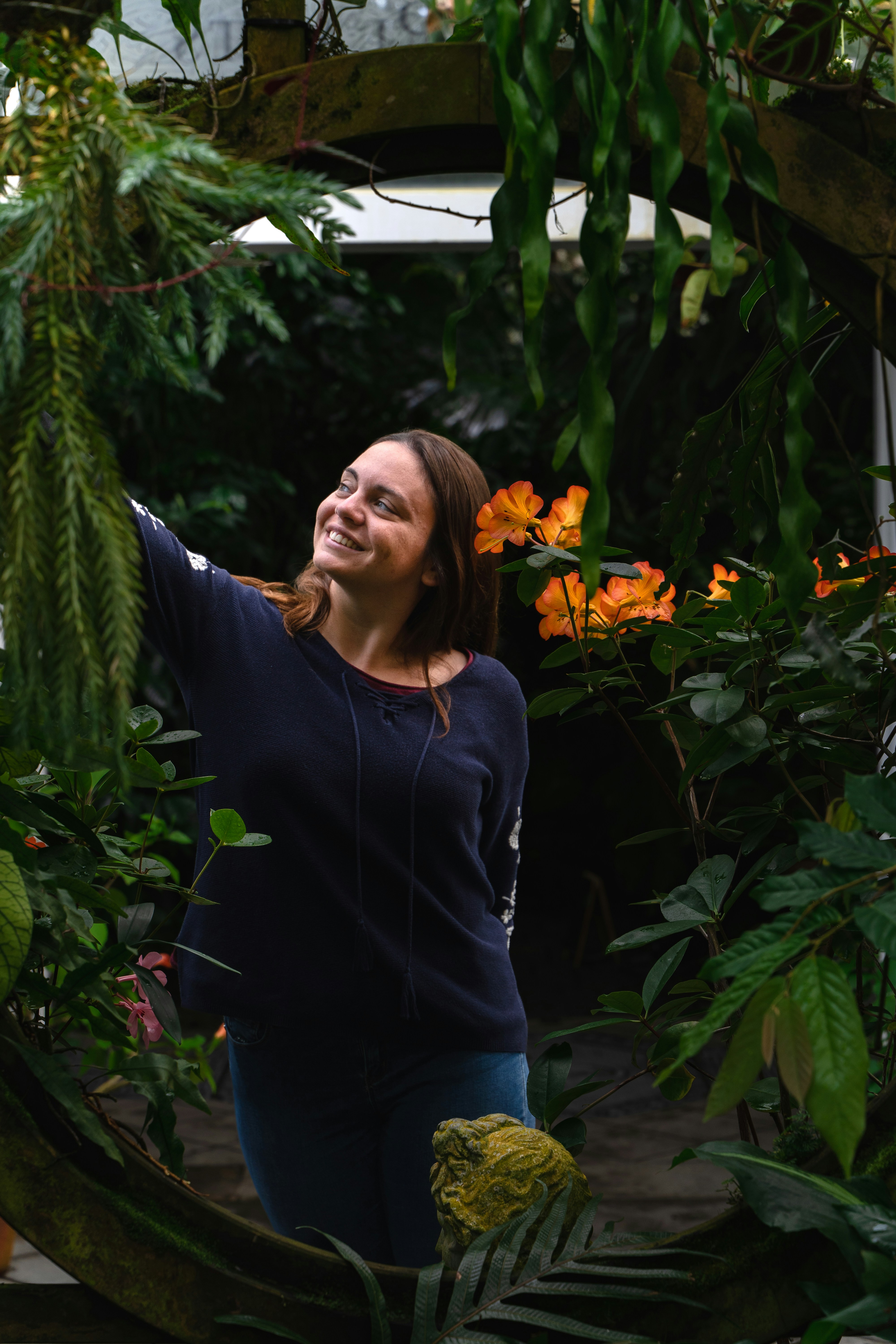 Portrait in a Green Arch: A Woman Reaching into a Lush Conservatory