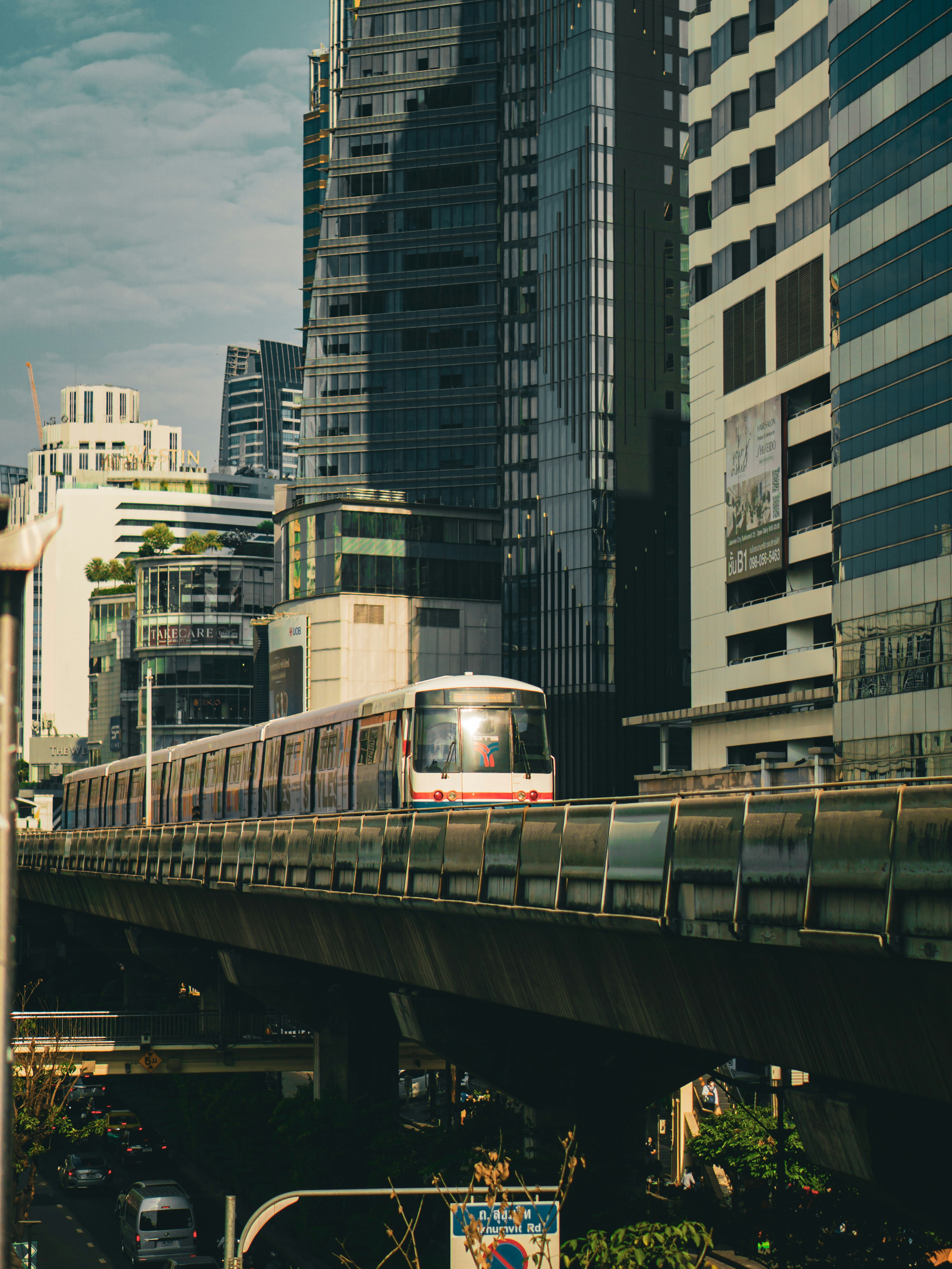 A train traveling over a bridge with tall buildings in the background ...