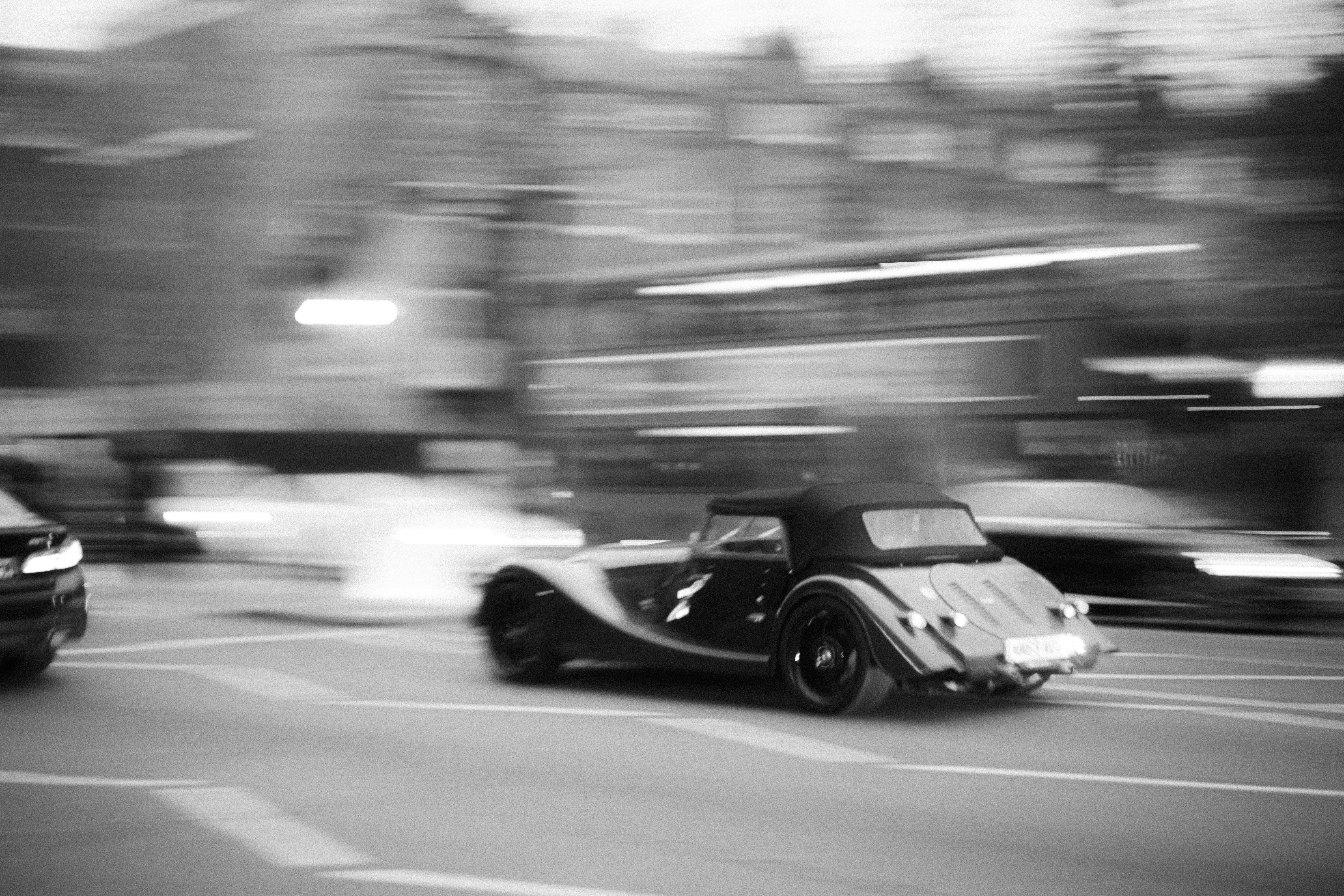 A black and white photo of a car driving down a street photo – Free ...