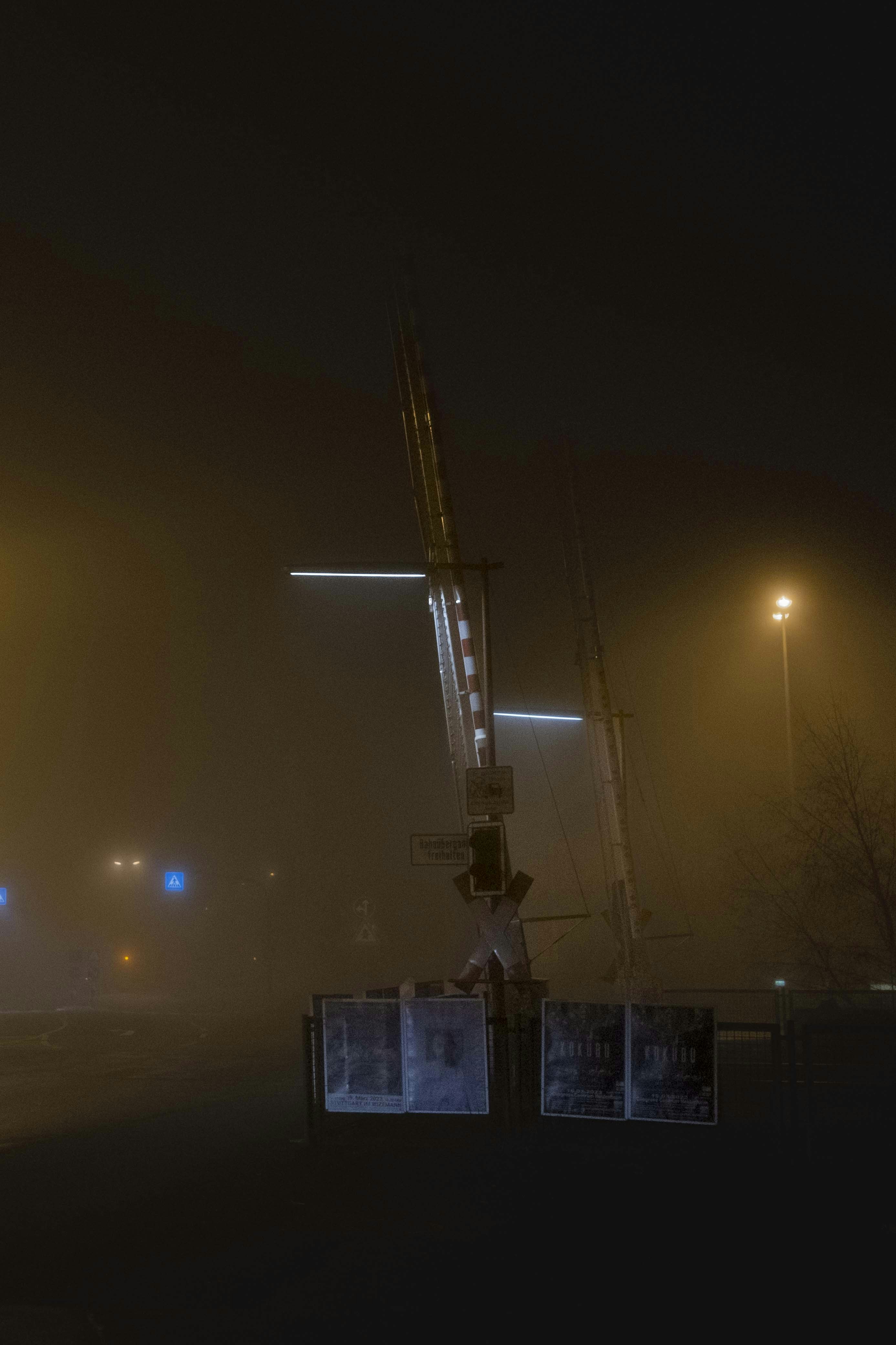Crane Under Fog: Neon Lines Mark a Nighttime Barricade