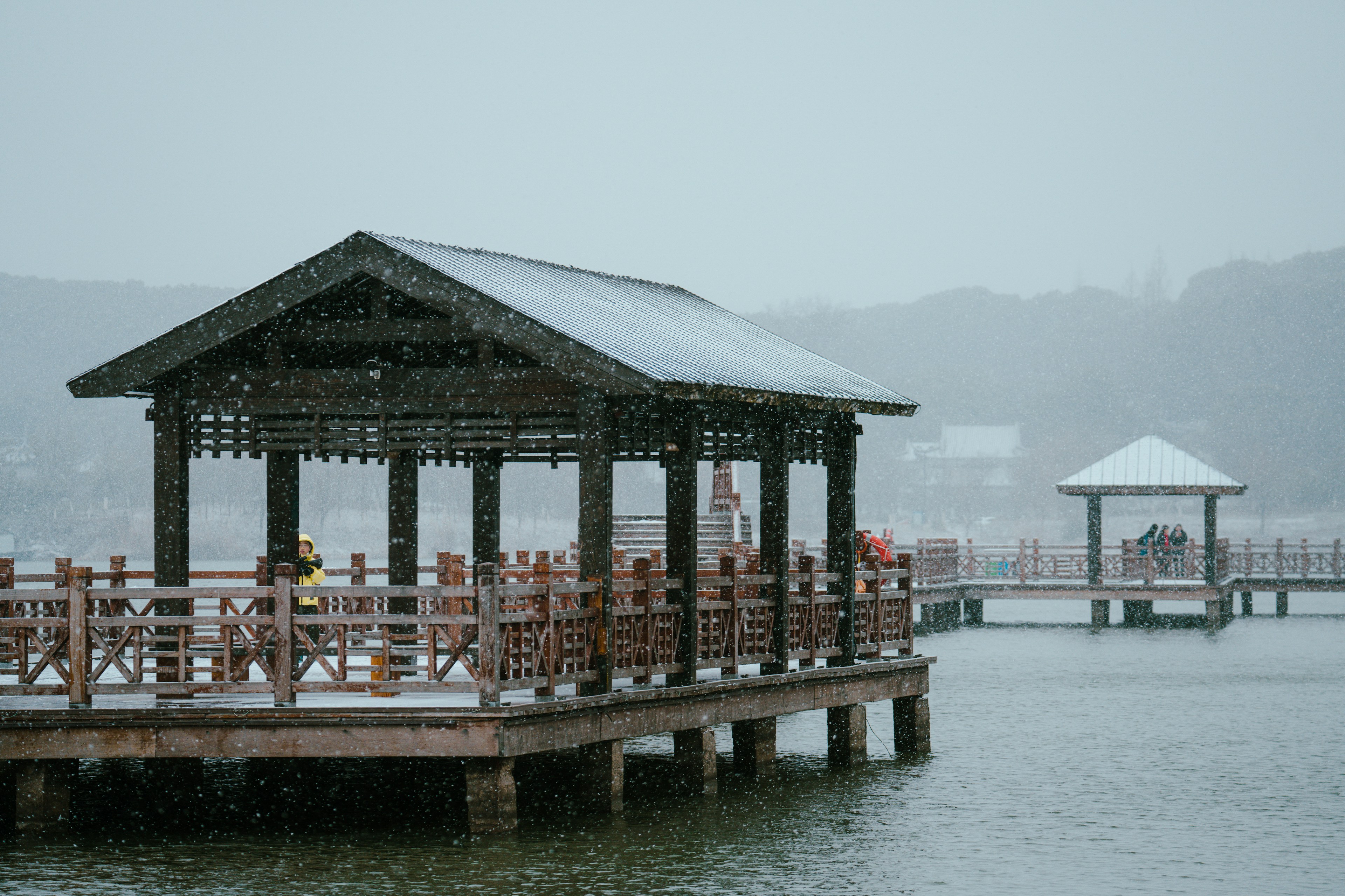 a wooden pier with a gazebo and people on it