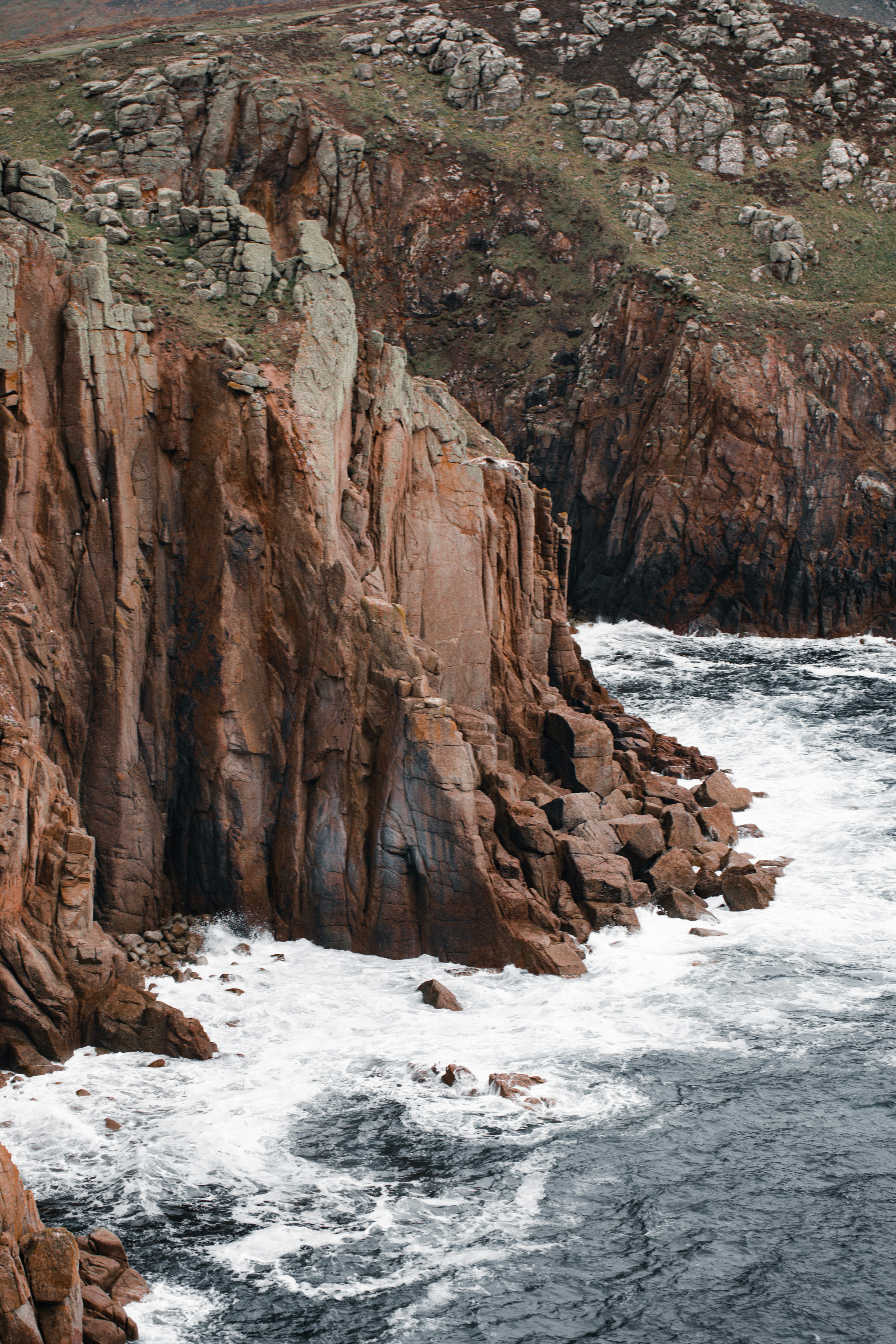 A large body of water next to a rocky cliff photo – Free Cliff Image on ...