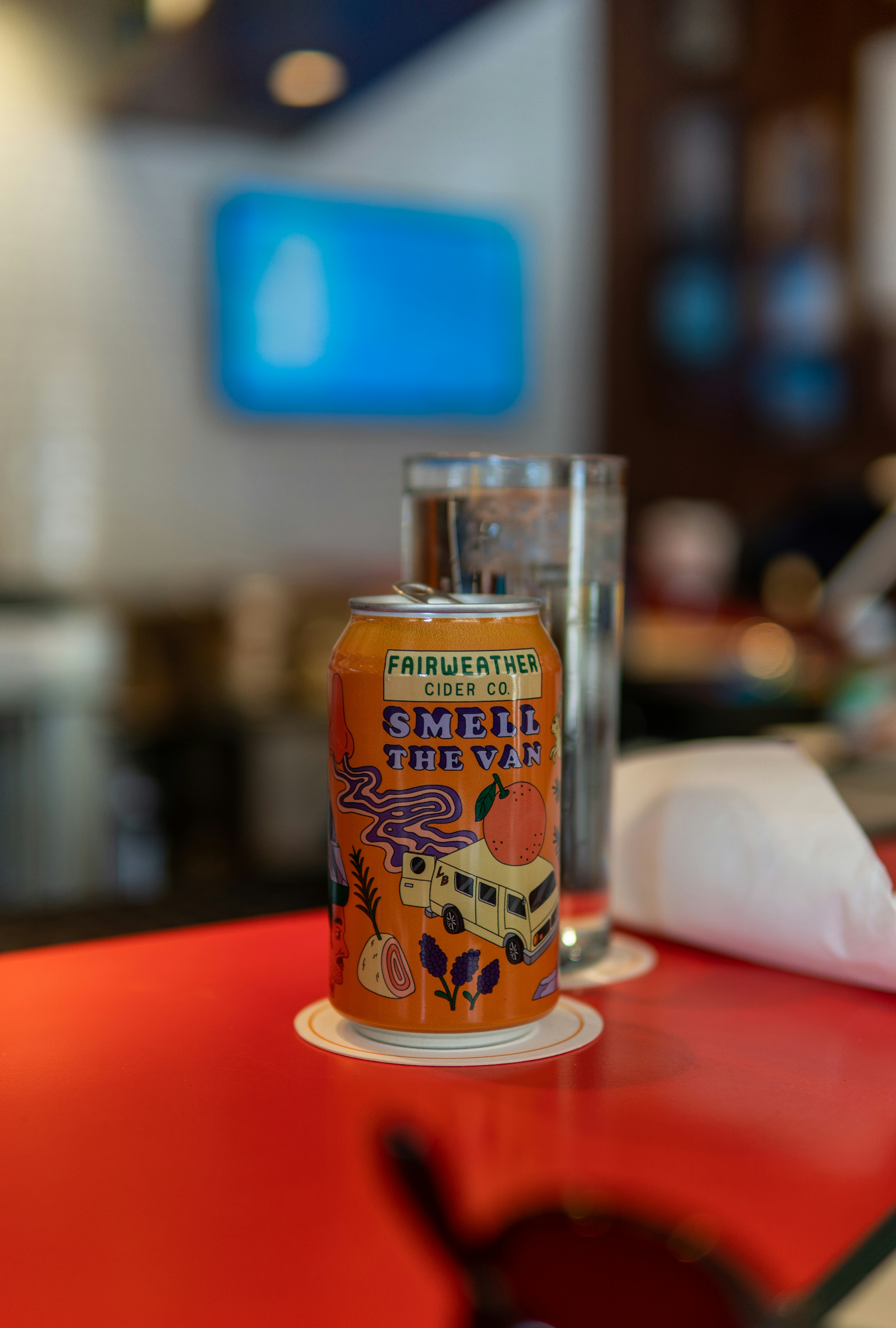 Smell the Van: A Citrus Cider Can Anchored on a Bold Red Table