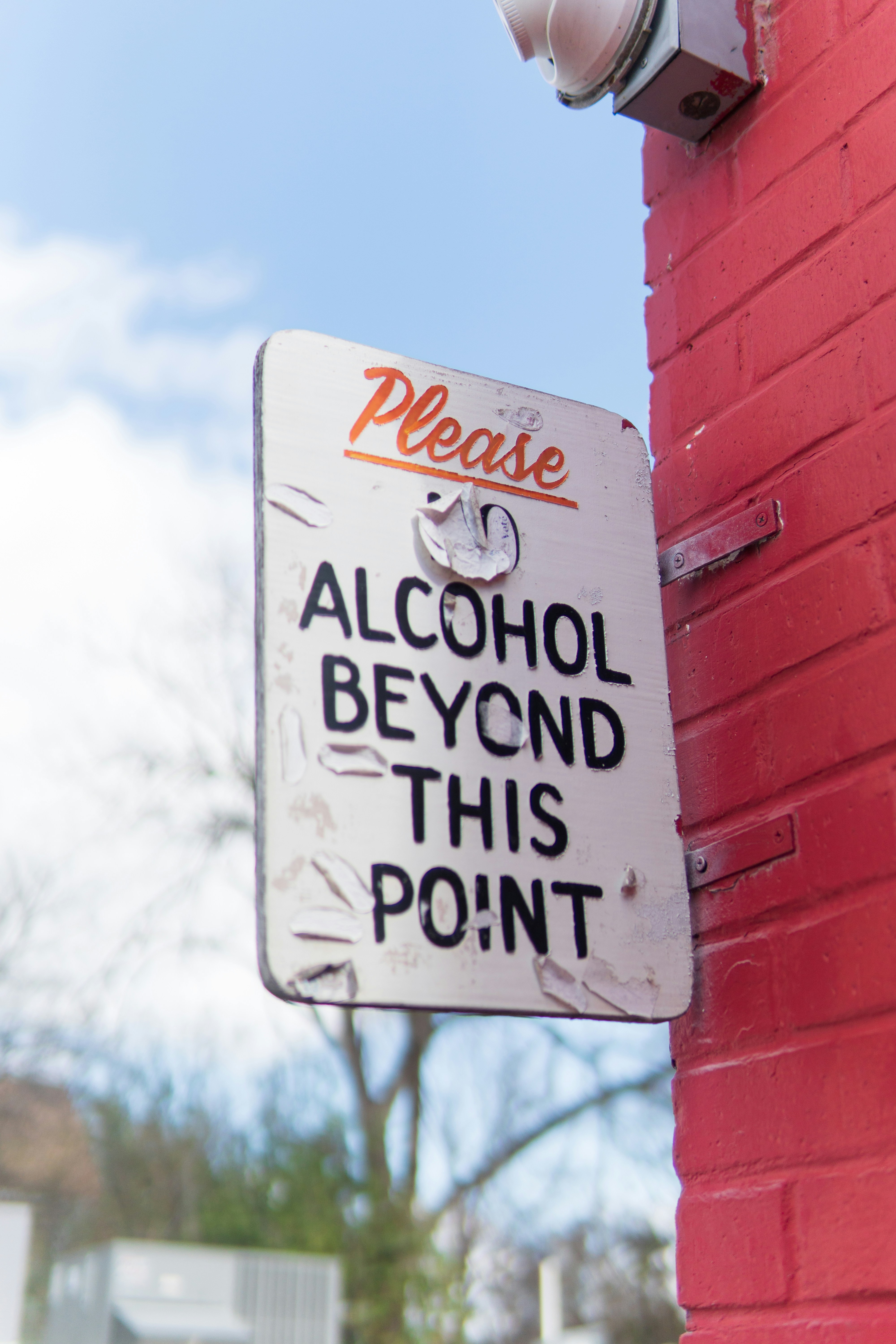 A sign on a red brick wall that says please alcohol beyond this point ...