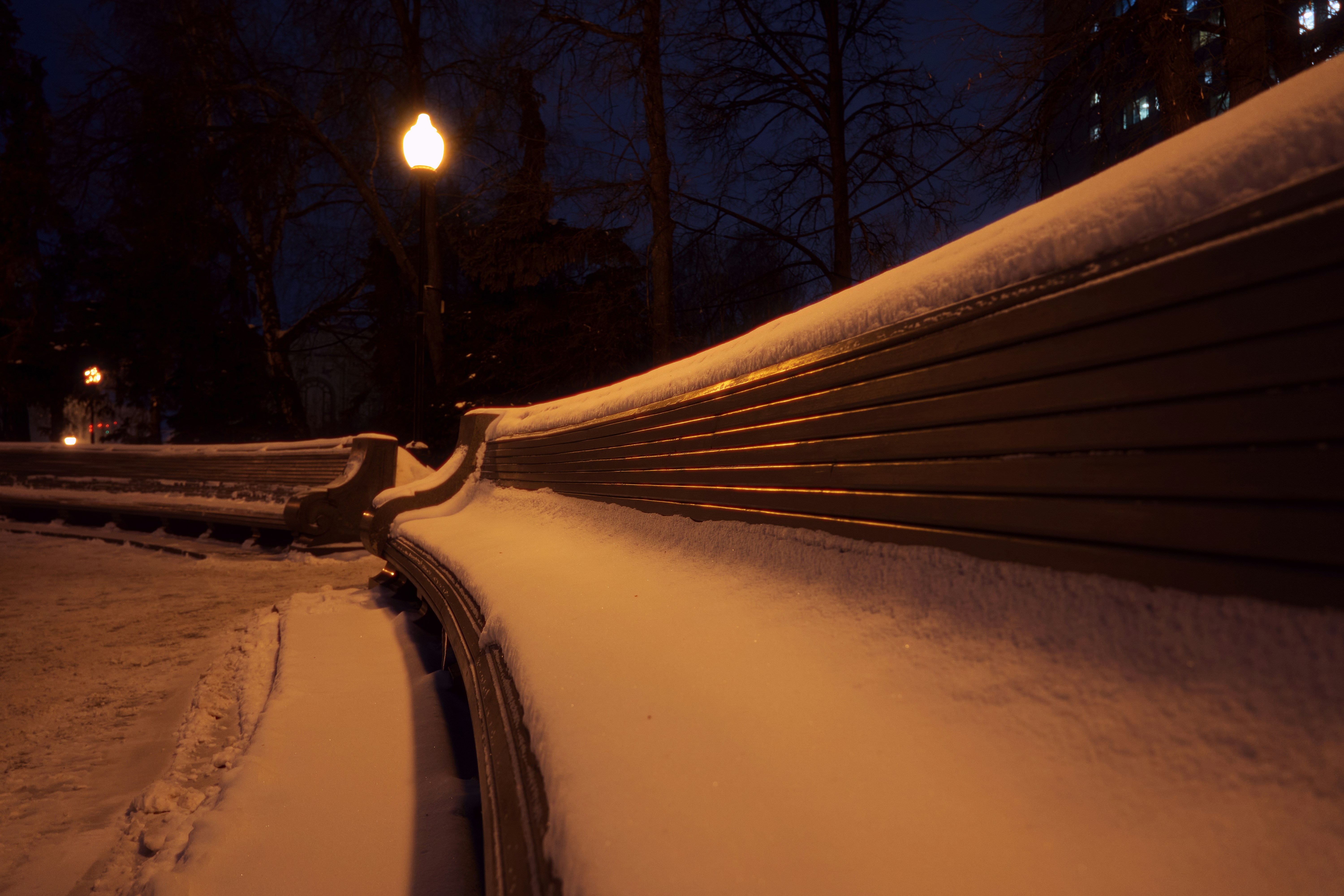 a park bench covered in snow at night