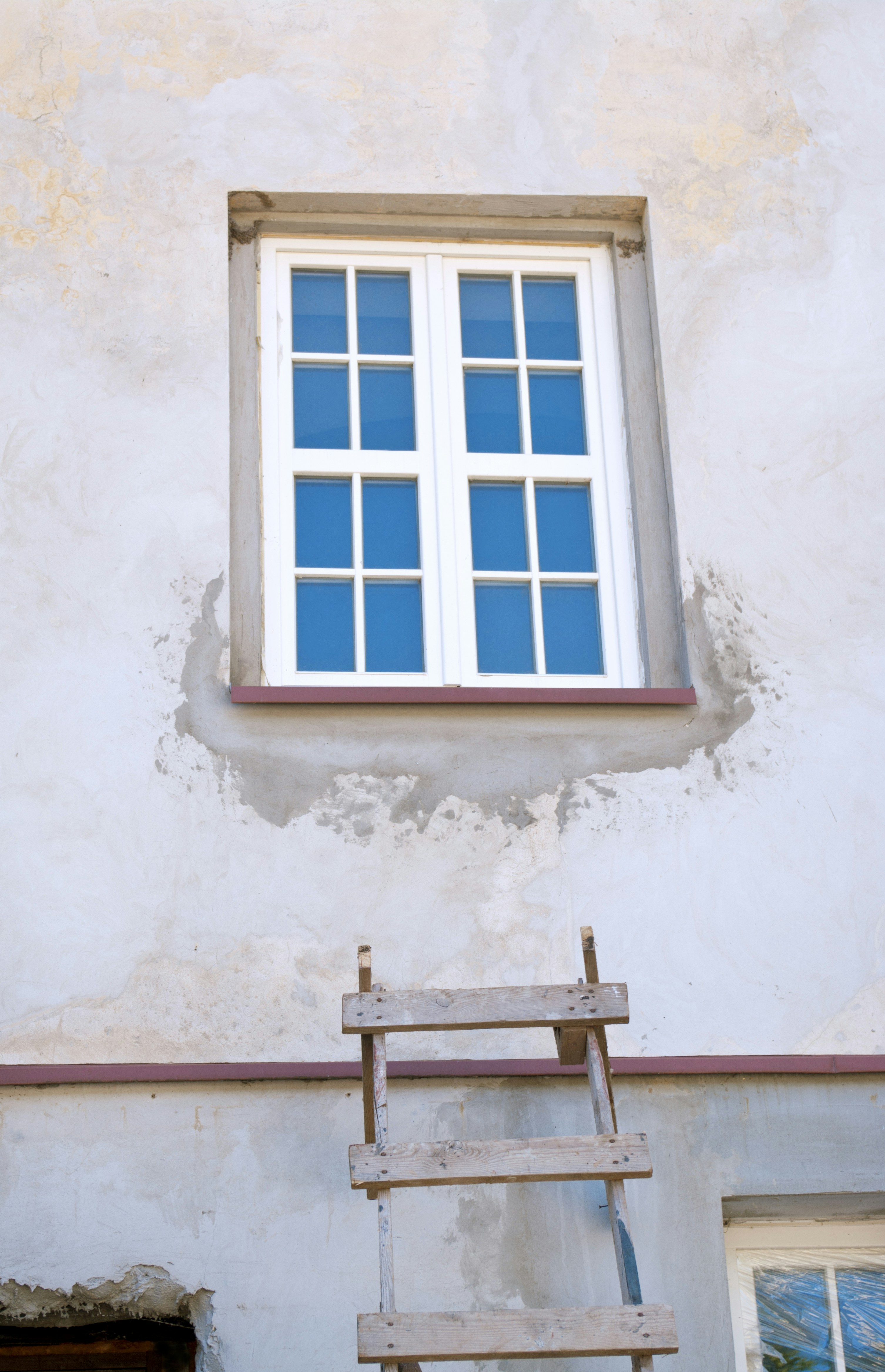 A ladder leaning against a wall with a window above it photo – Free ...