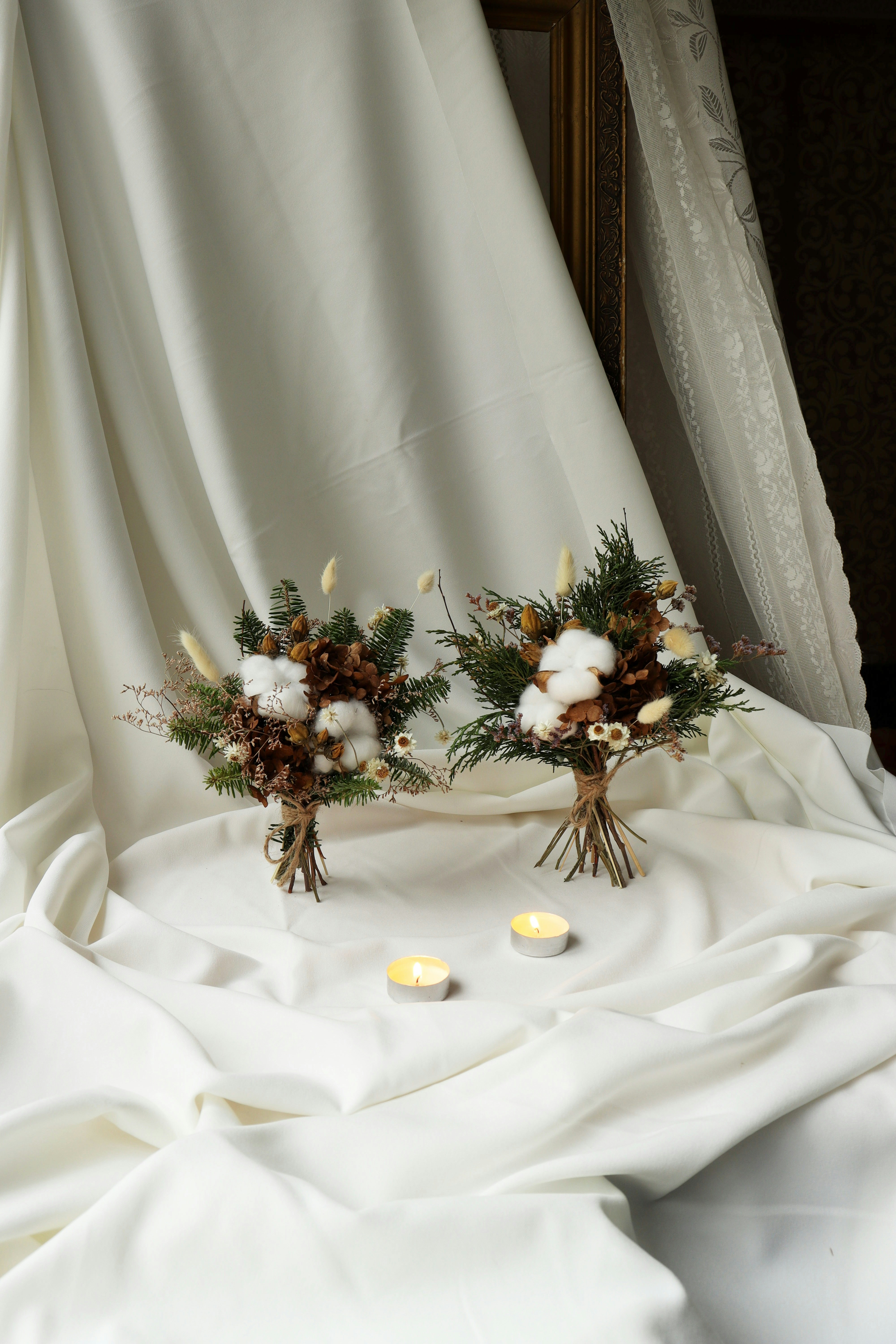 Twin rustic bouquets on a satin stage bathed in candlelight