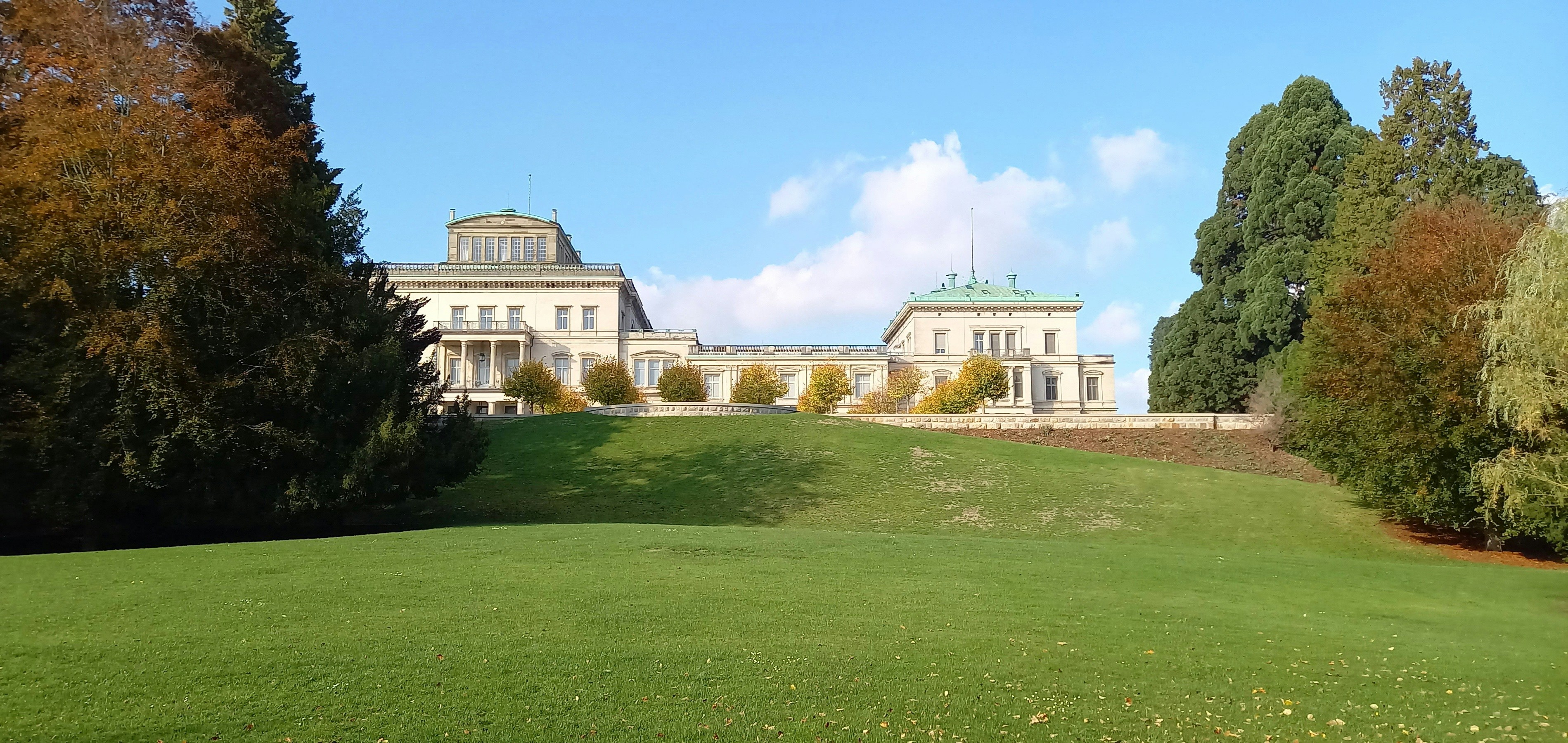 Elegant white building on a sprawling green lawn under a clear blue sky.