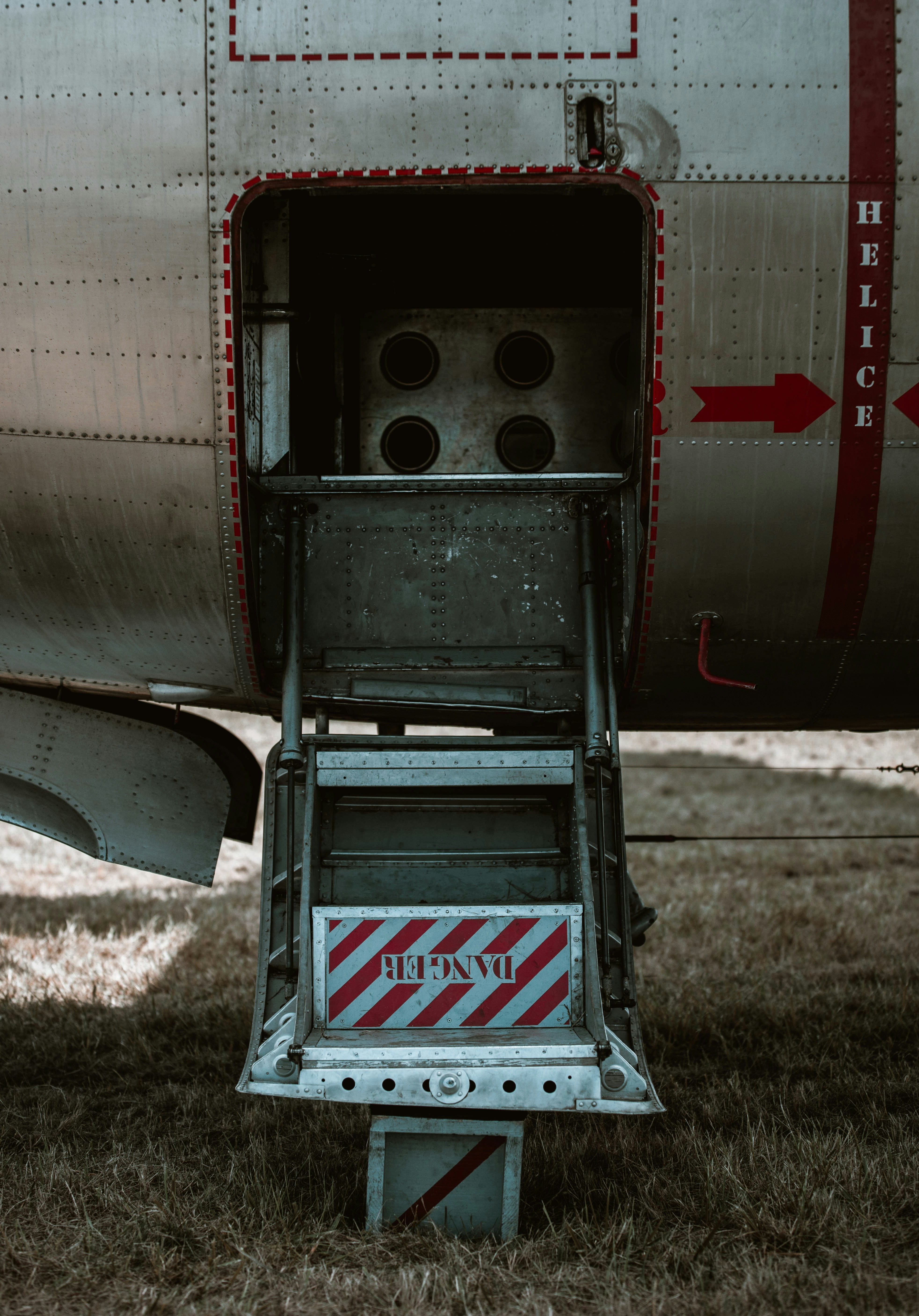 Open Hatch, Worn Aluminum: The Staircase Clings to a Jet's Weathered Belly