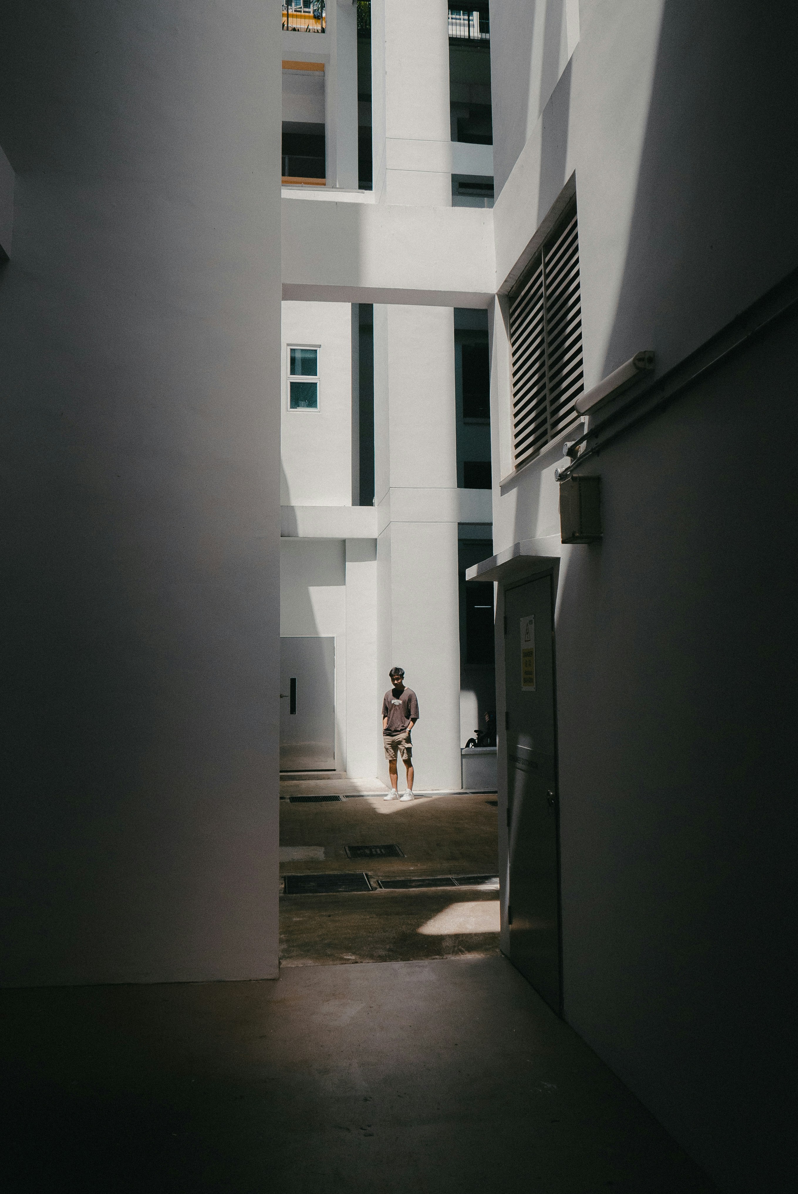 A man standing in a doorway between two buildings photo – Free Tiong ...