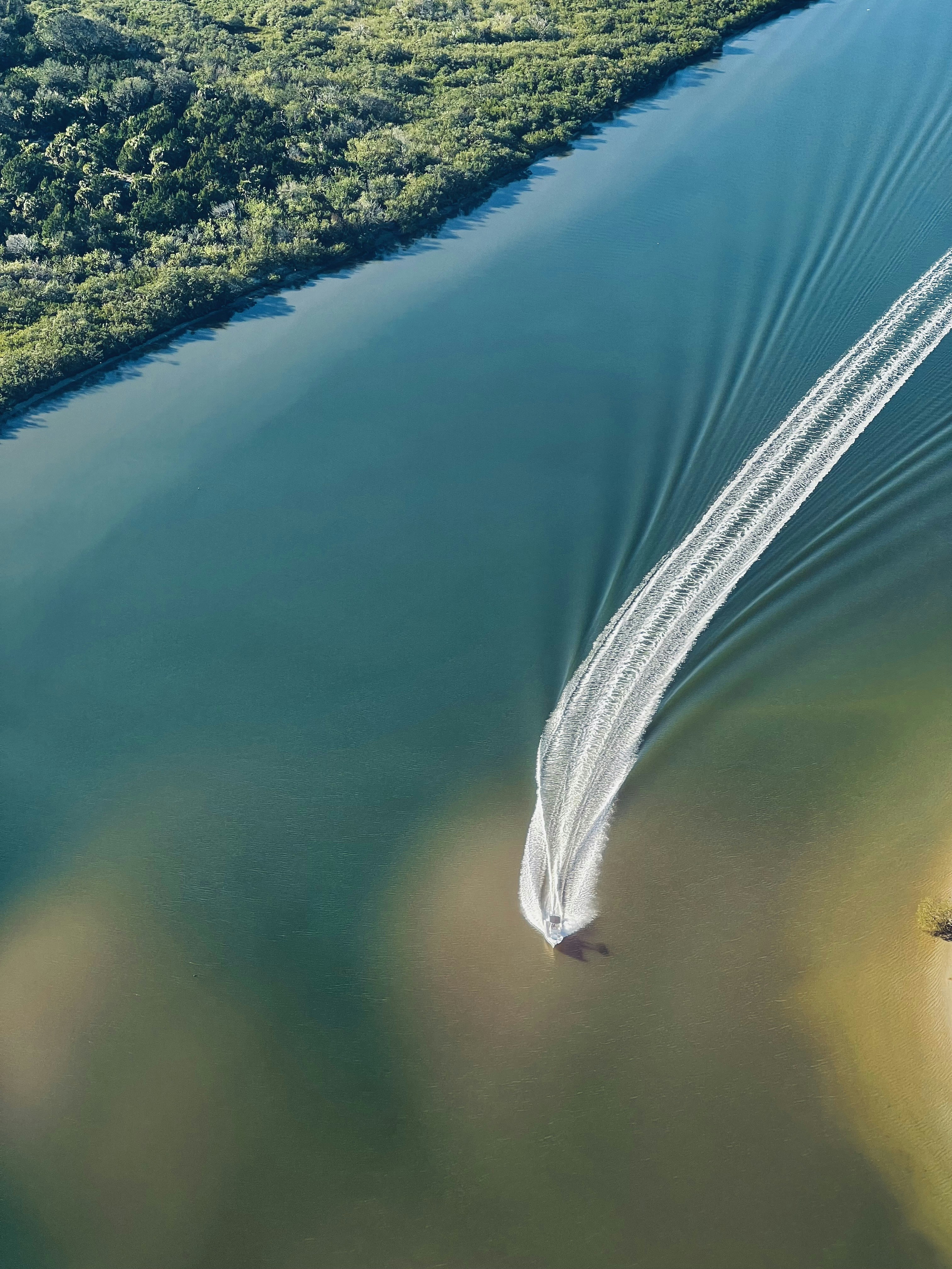 Emerald Wake: Aerial Portrait of a Lone Speedboat Tracing Twin Veils Across Turquoise Water