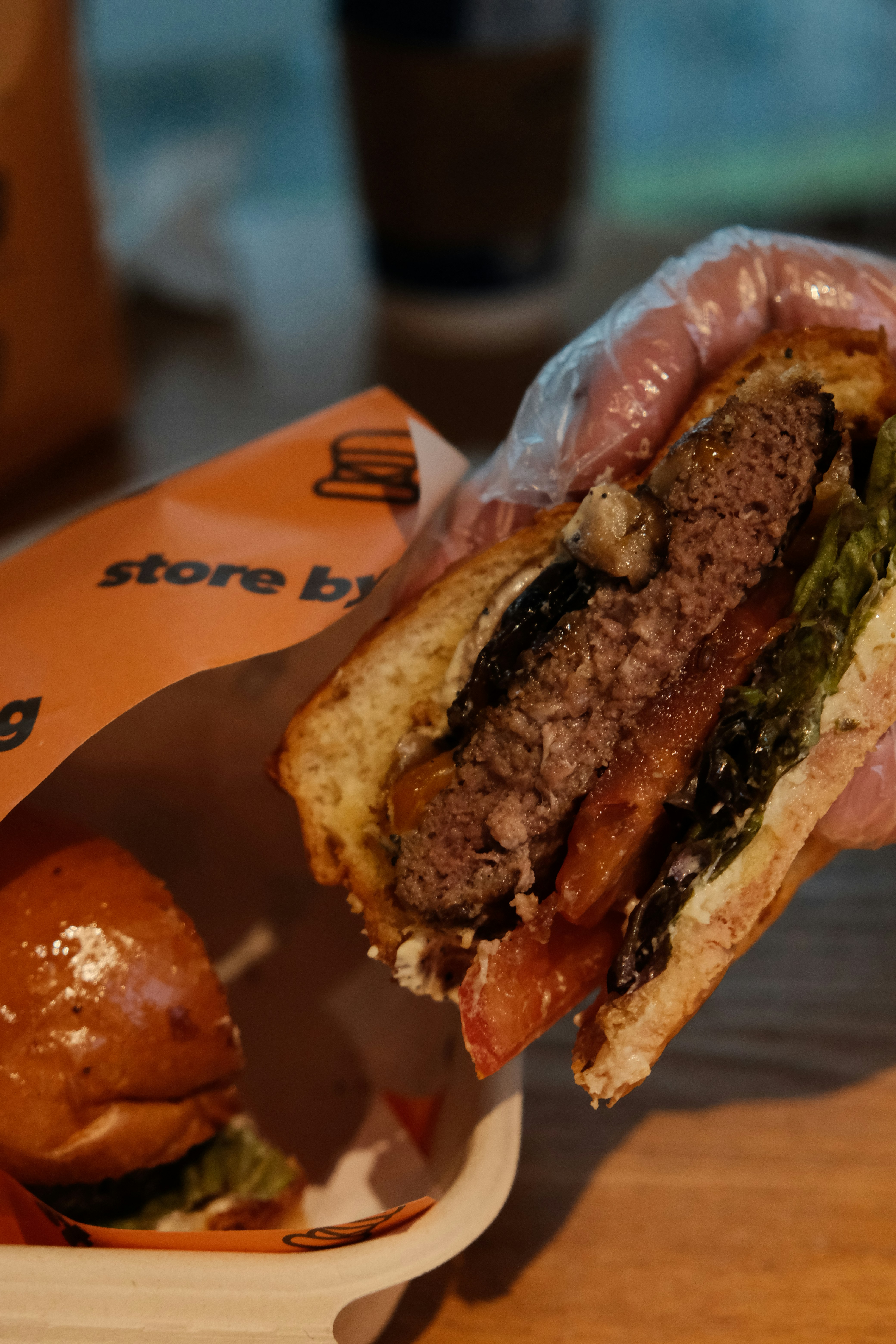 A hand holding a half eaten hamburger in a paper container photo – Free ...