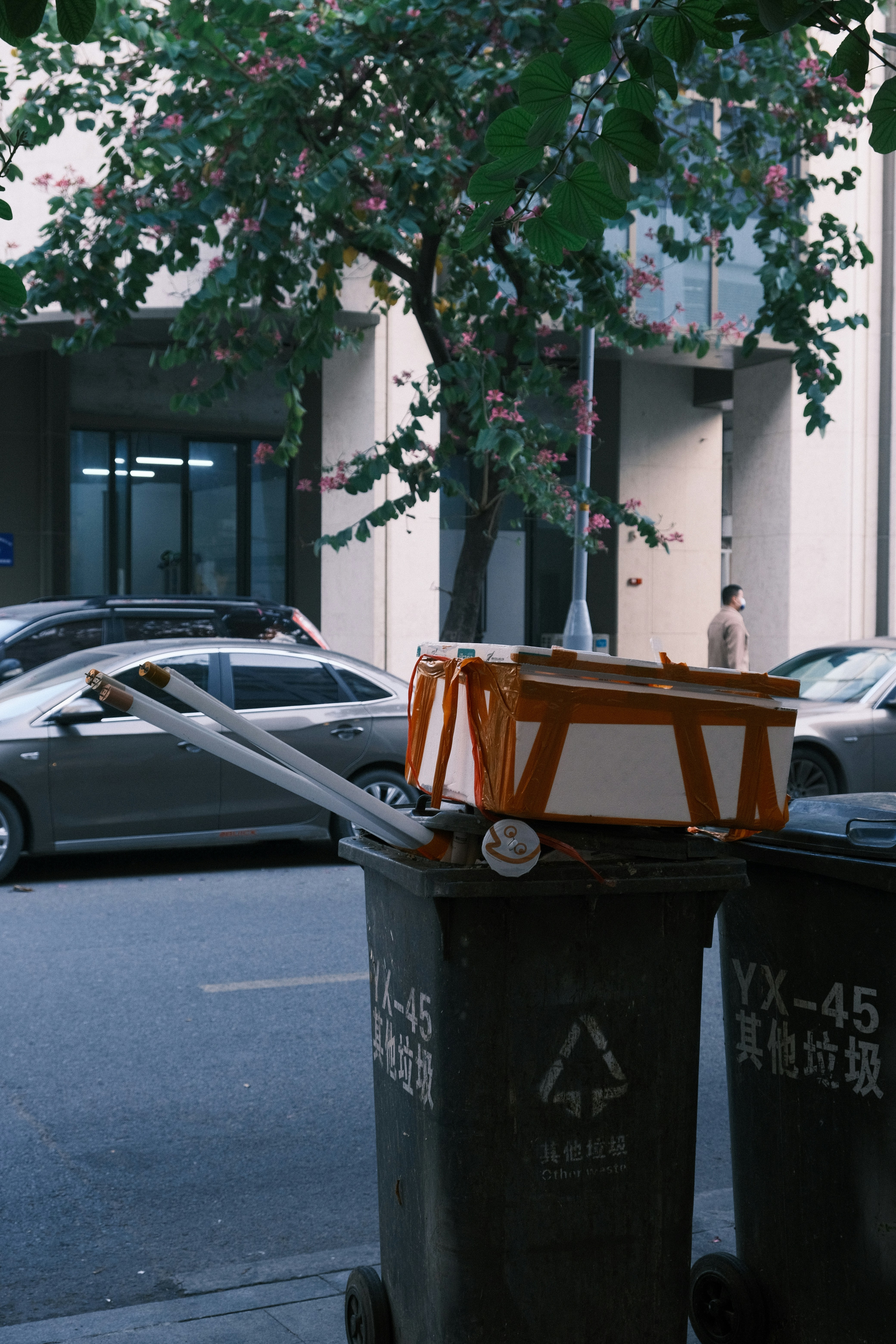 a couple of trash cans sitting on the side of a road