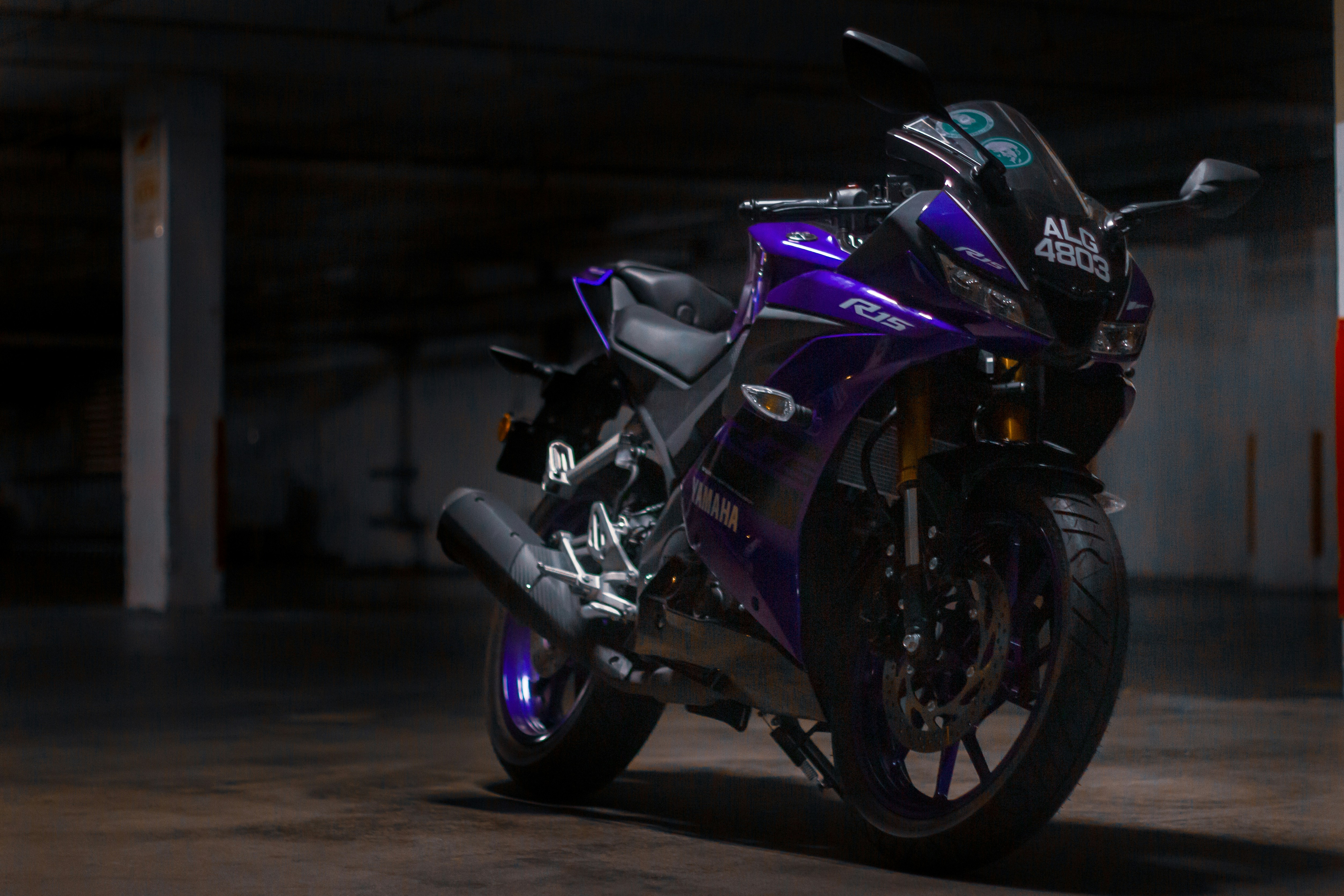 Purple motorcycle stationed in a dimly lit parking garage, highlighting its sleek design.