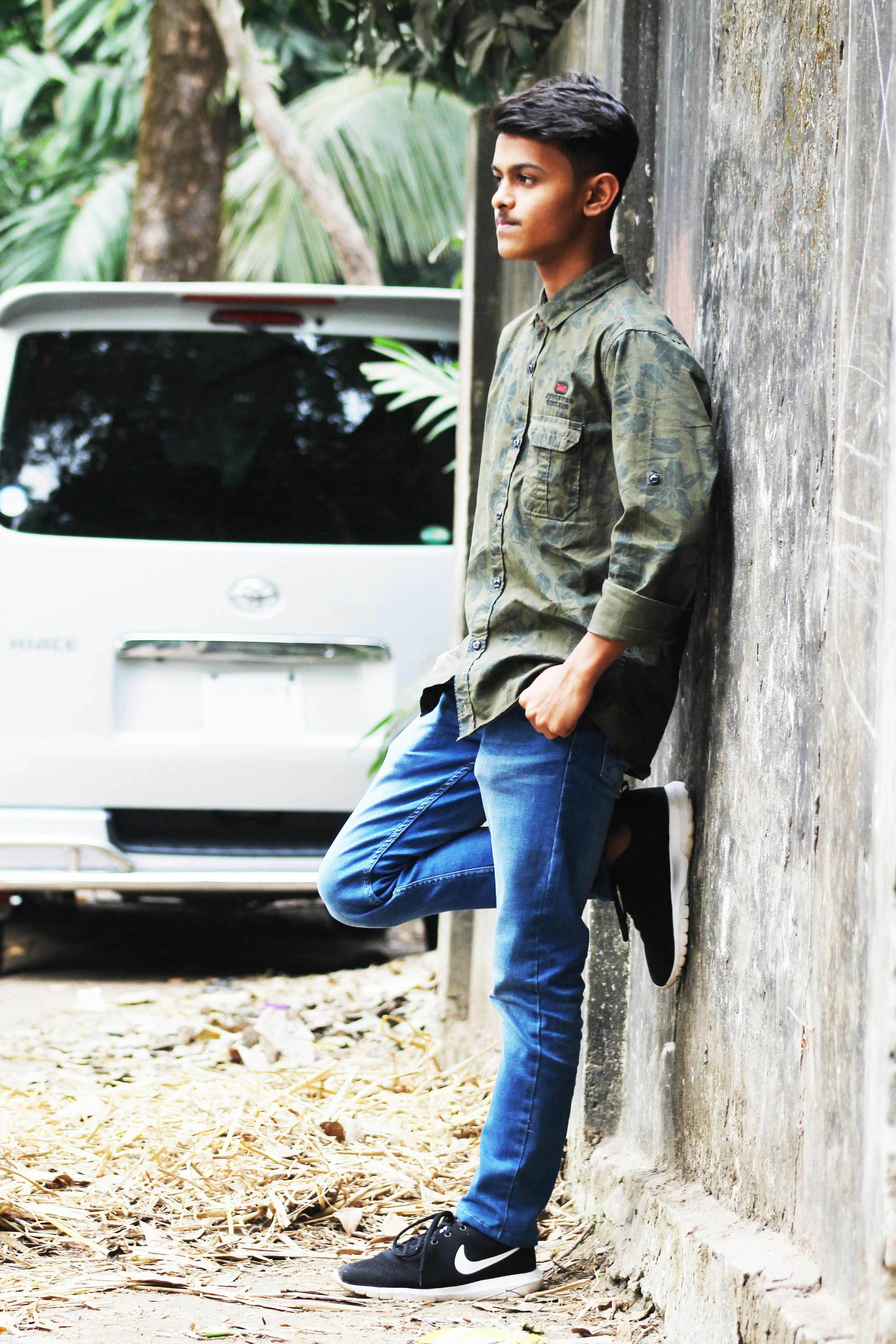 Youthful Street Portrait Leaning Against Concrete with a White SUV in the Background