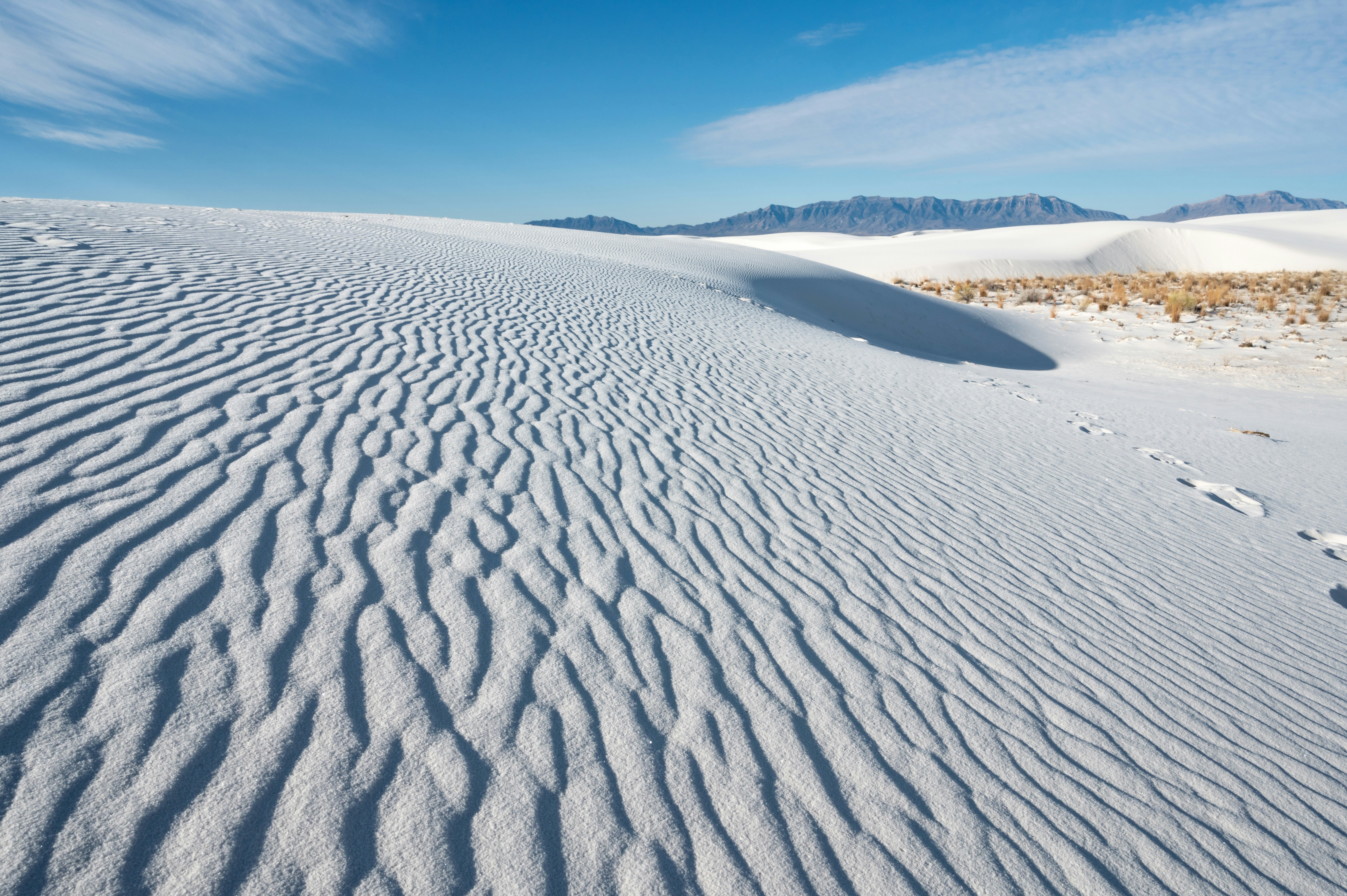 A wide expanse of white sand with mountains in the background photo ...