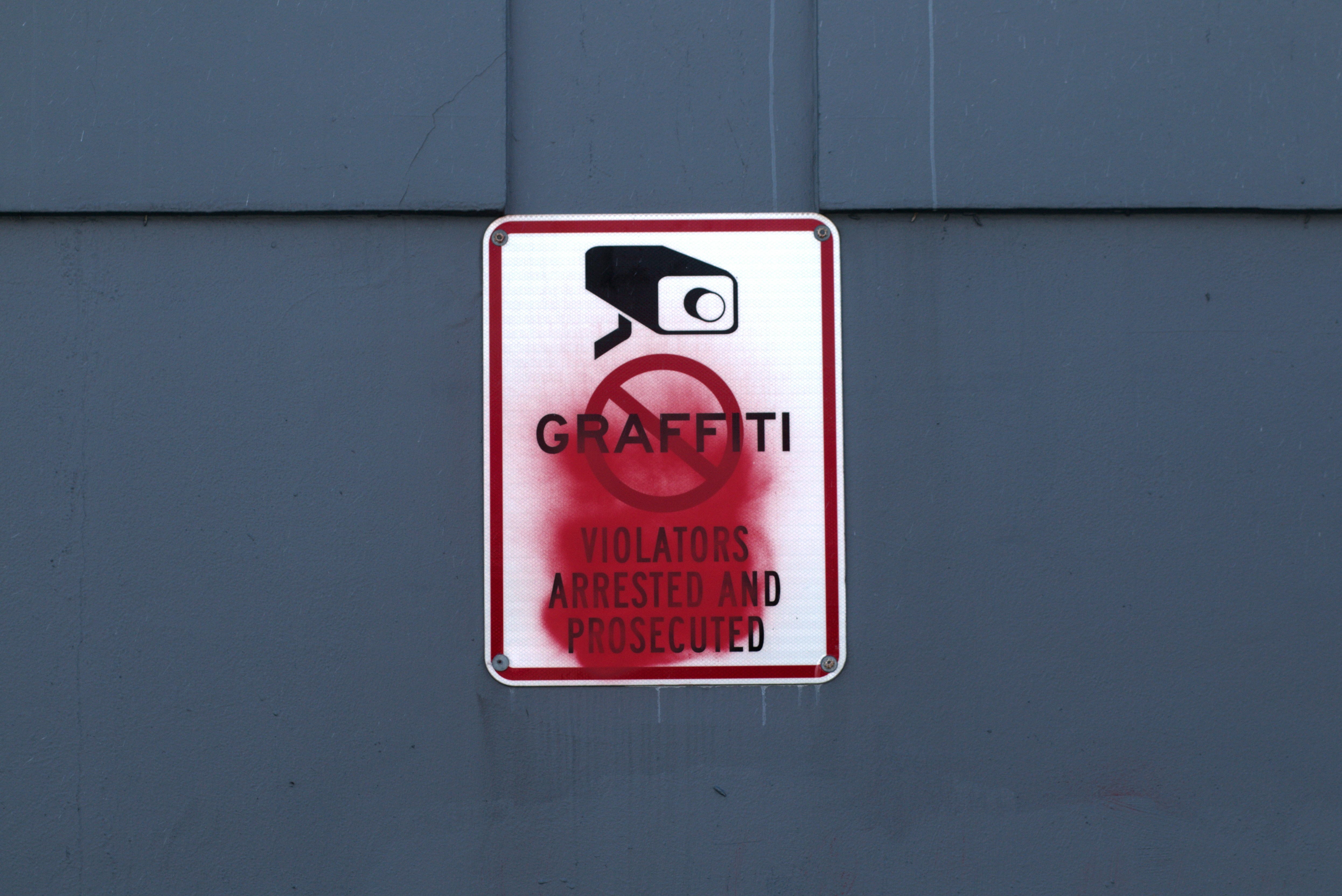 Red-Caulked Warning: Graffiti Sign on a Slate Wall