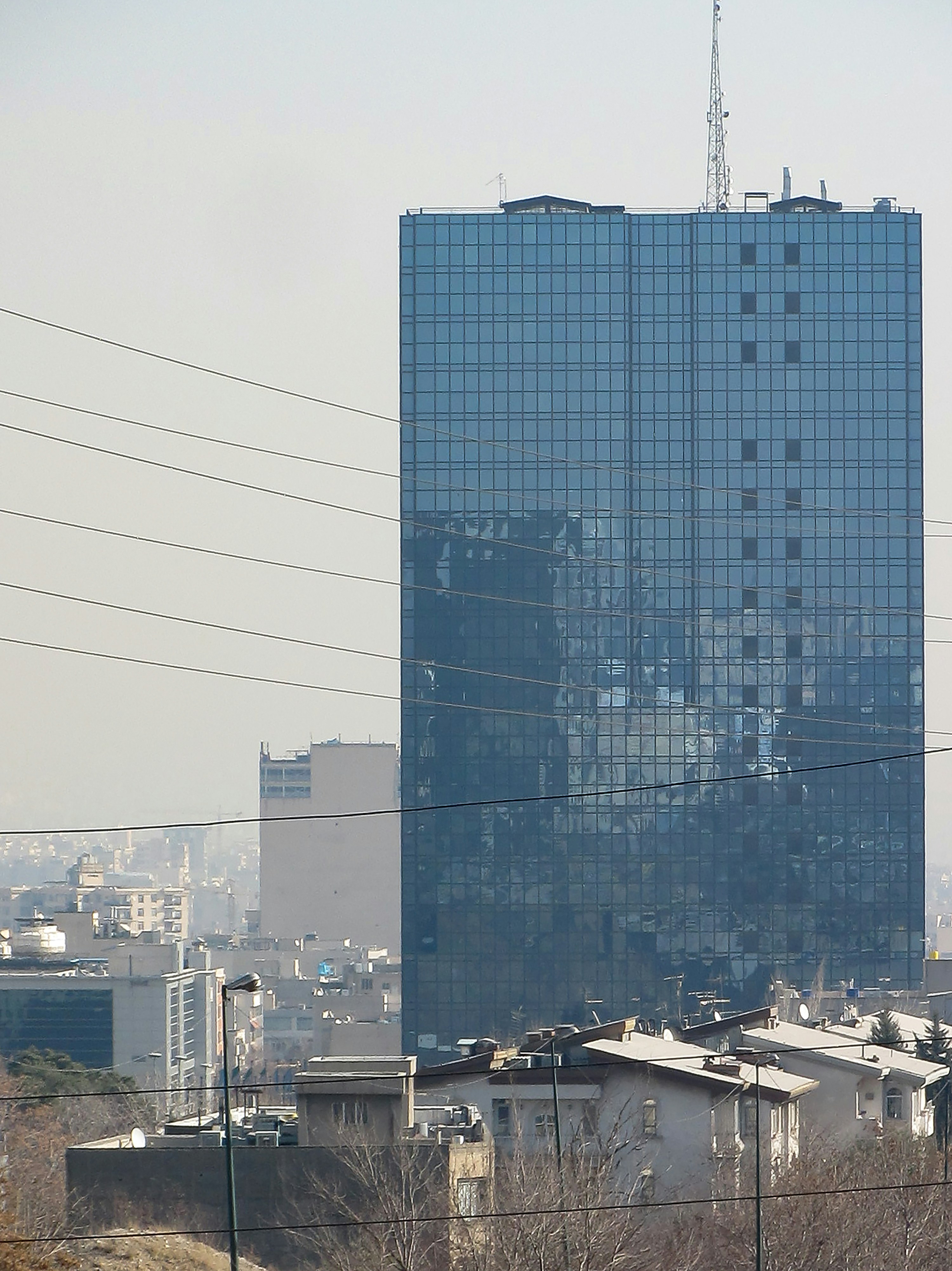 A tall blue-glass office tower dominates the city skyline behind a cluster of low-rise buildings.