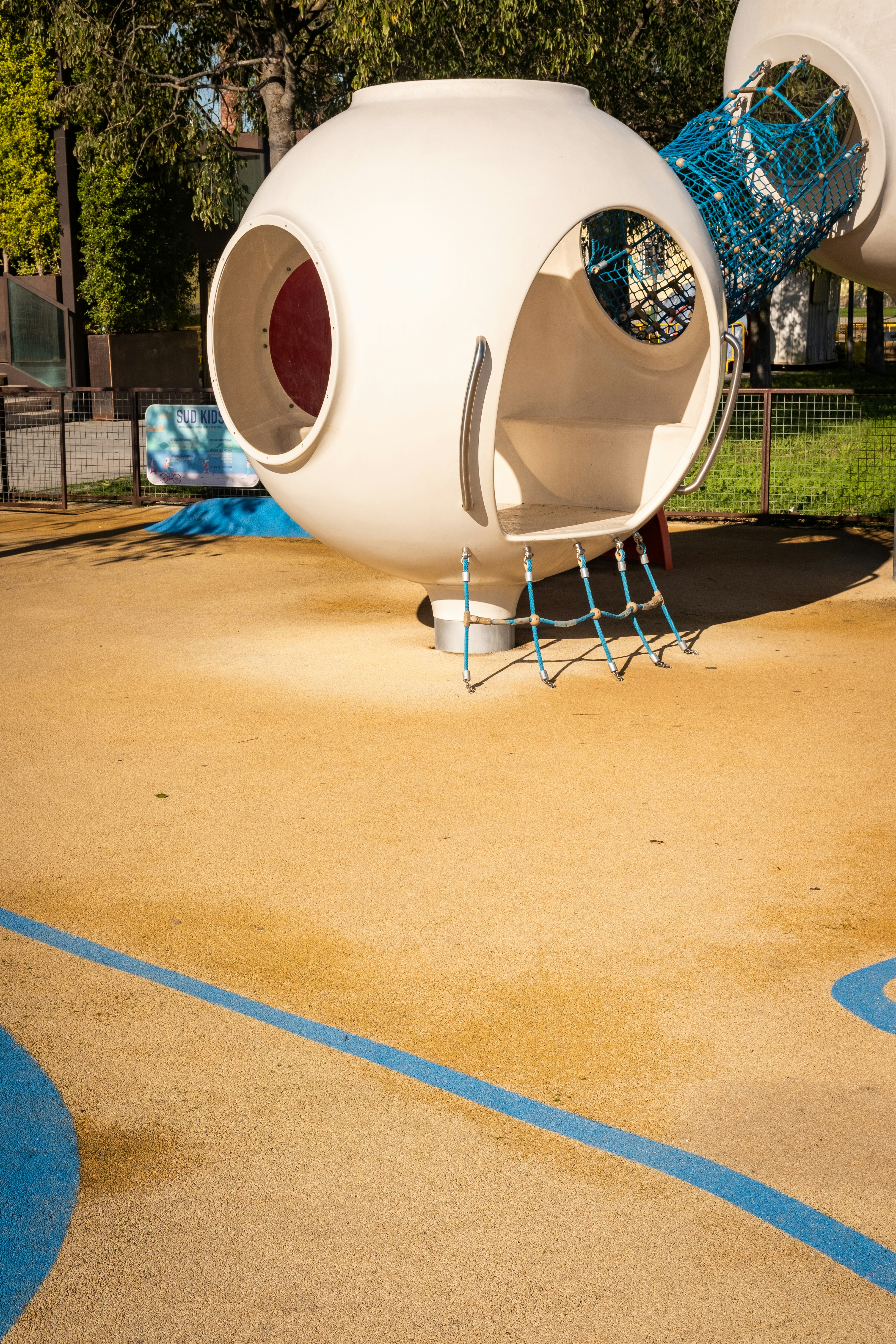 Sunlit Sphere Playground: A White Orb and a Blue Net Tunnel