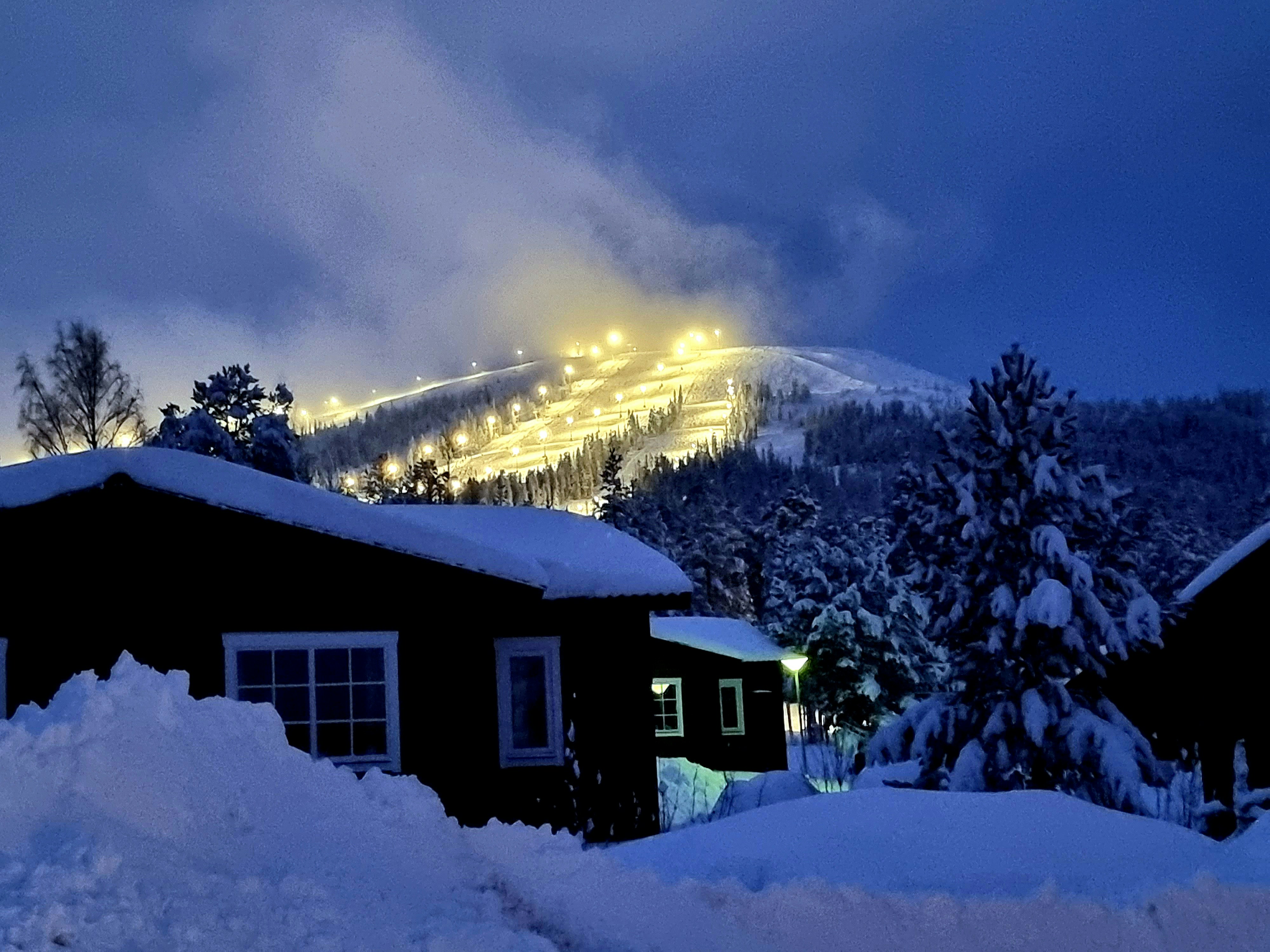Snow-Capped Summit Lights: Night Ski Run Illuminates a Quiet Village