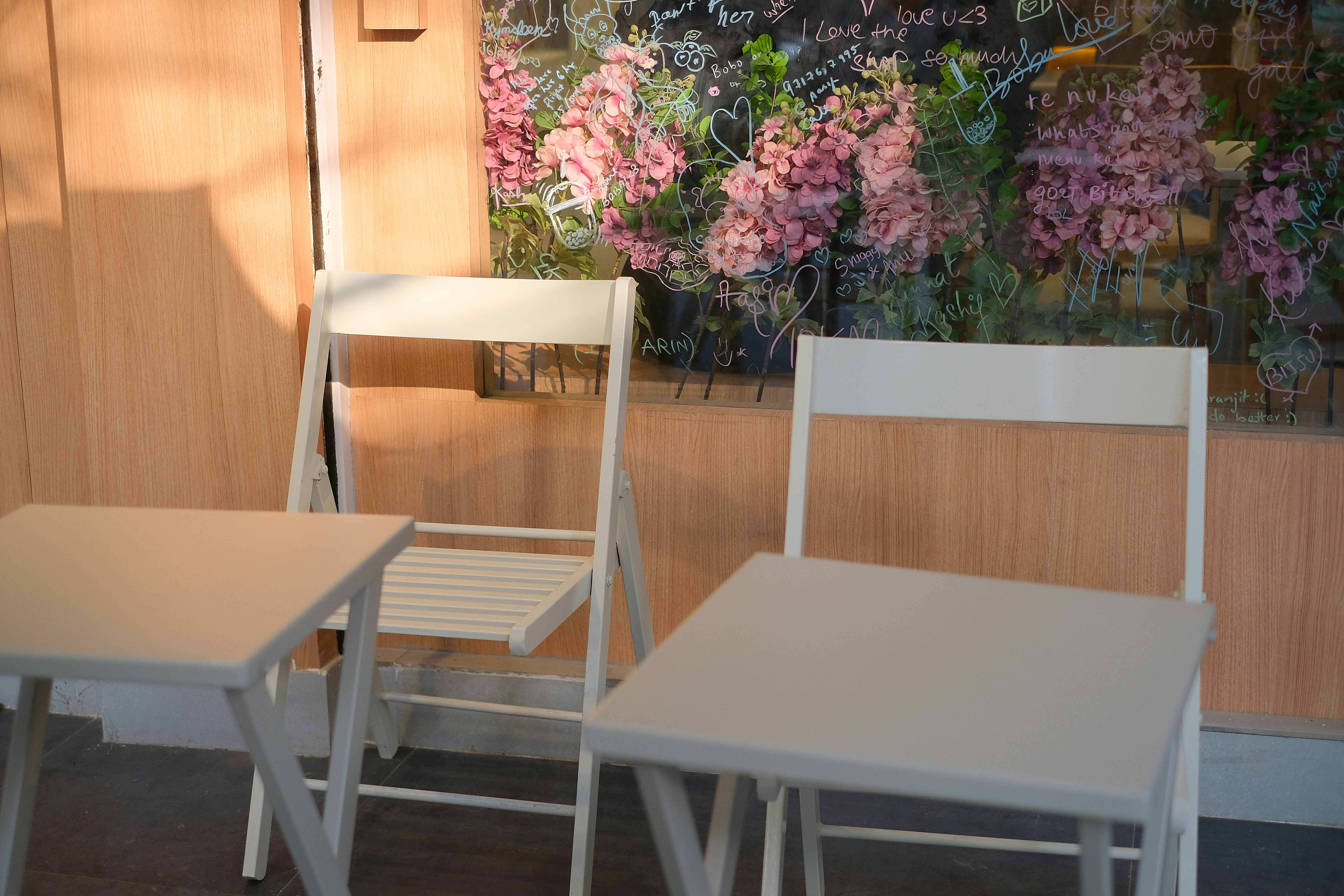 Sunlit White Café Terrace Framed by Chalkboard Flowers