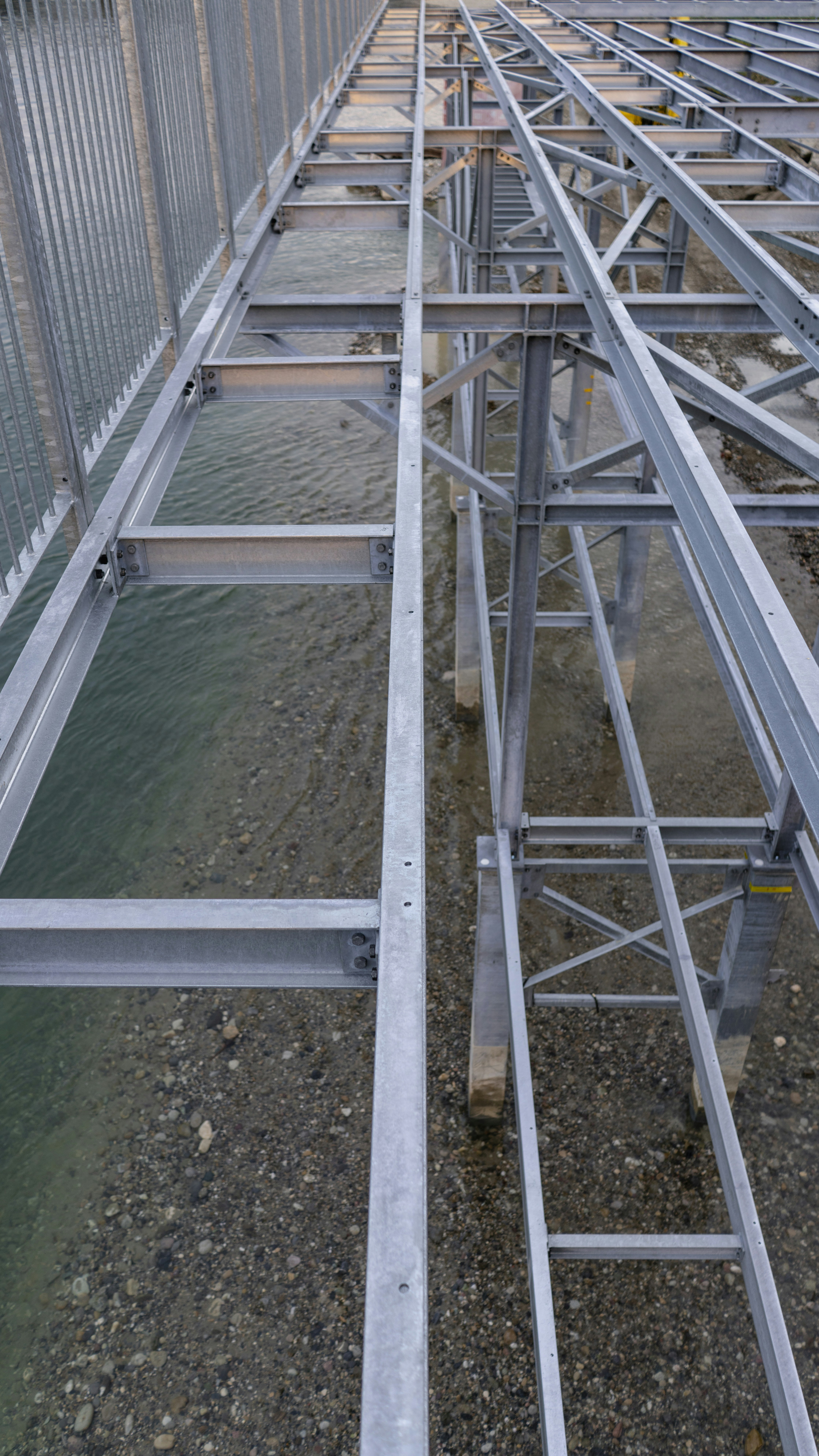 A row of metal structures sitting next to a body of water photo – Free ...